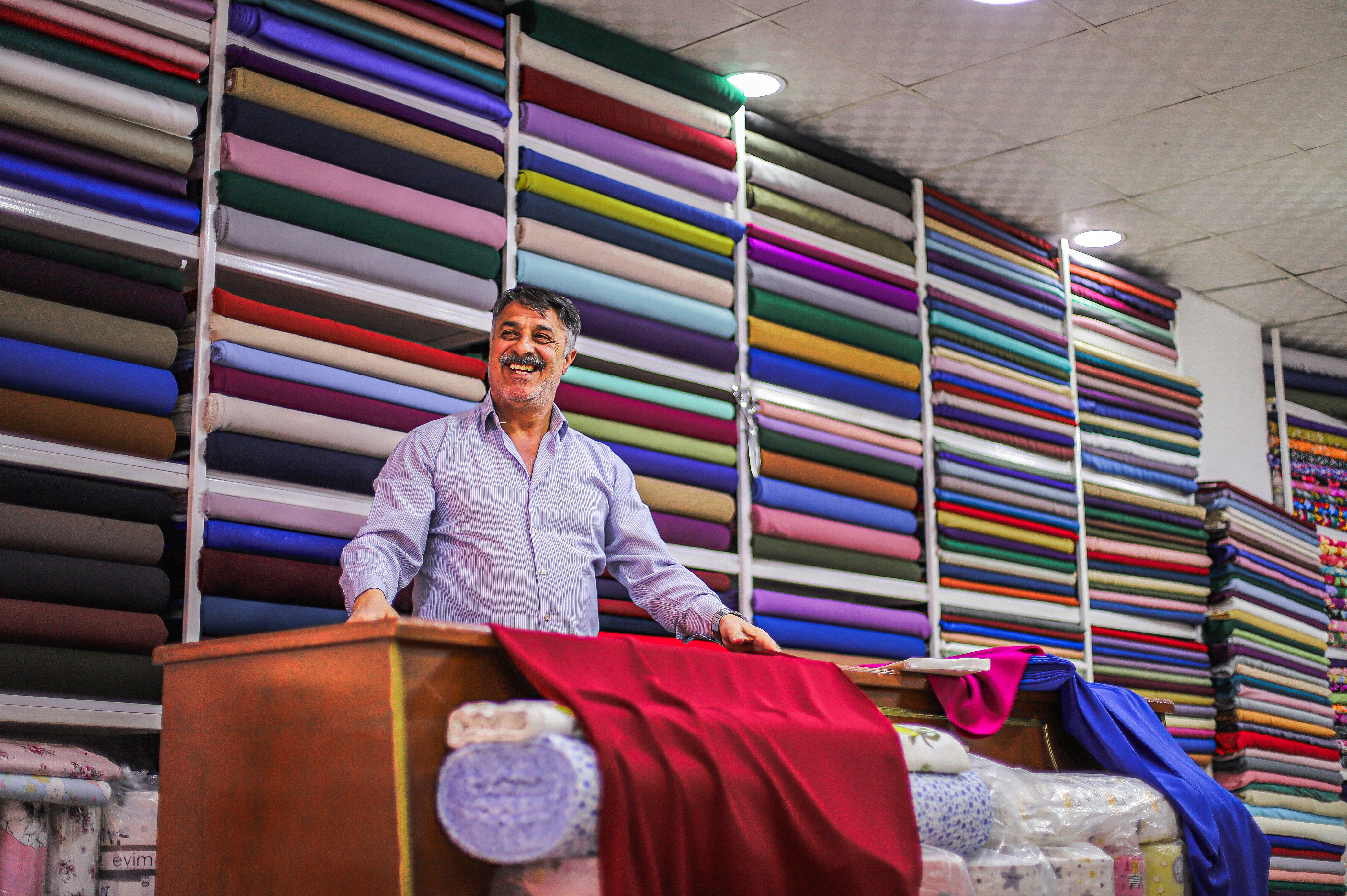 Smiling Shopkeeper in Turkish Fabric Store · Free Stock Photo