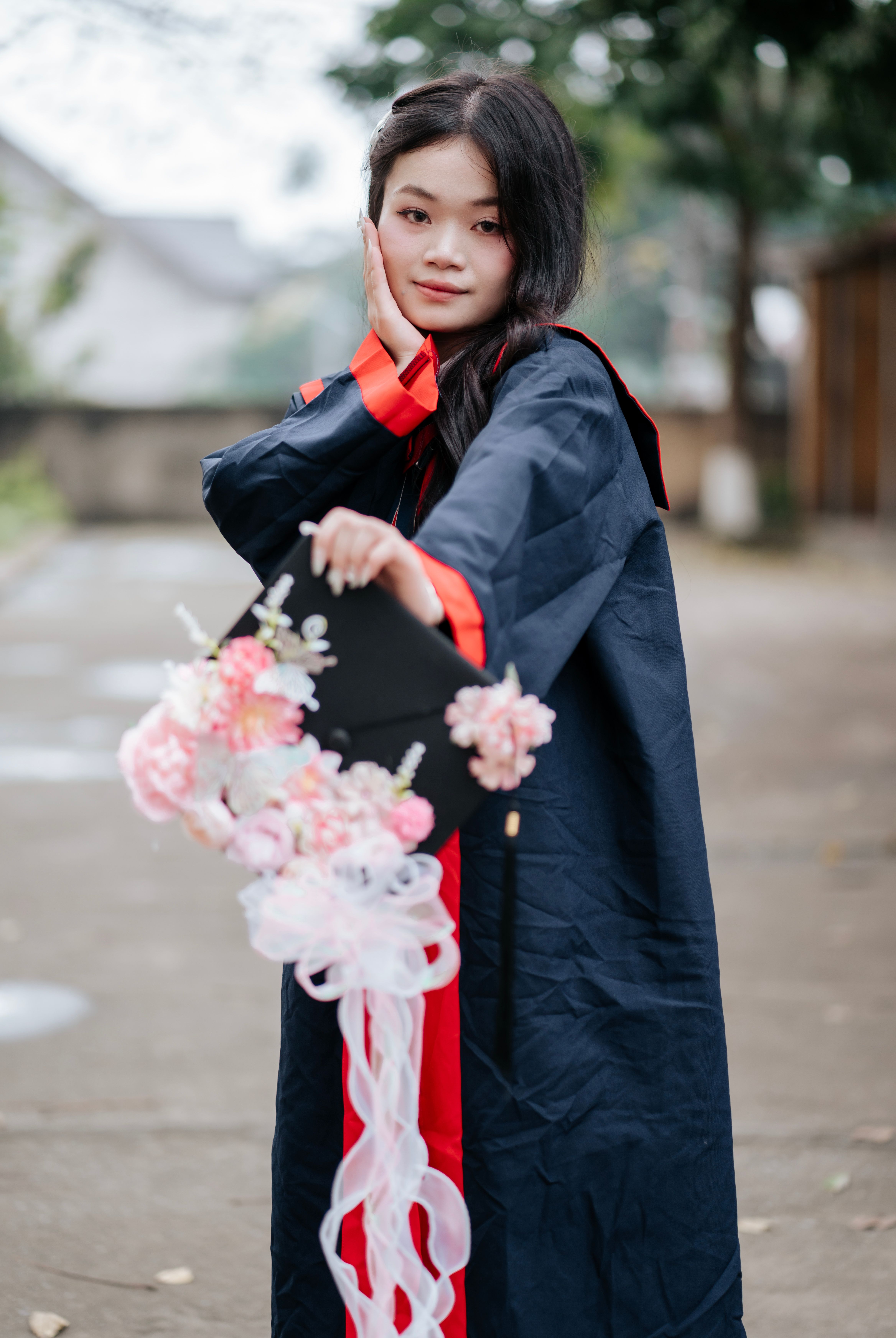 Young Graduate Celebrating Outdoors with Flowers · Free Stock Photo