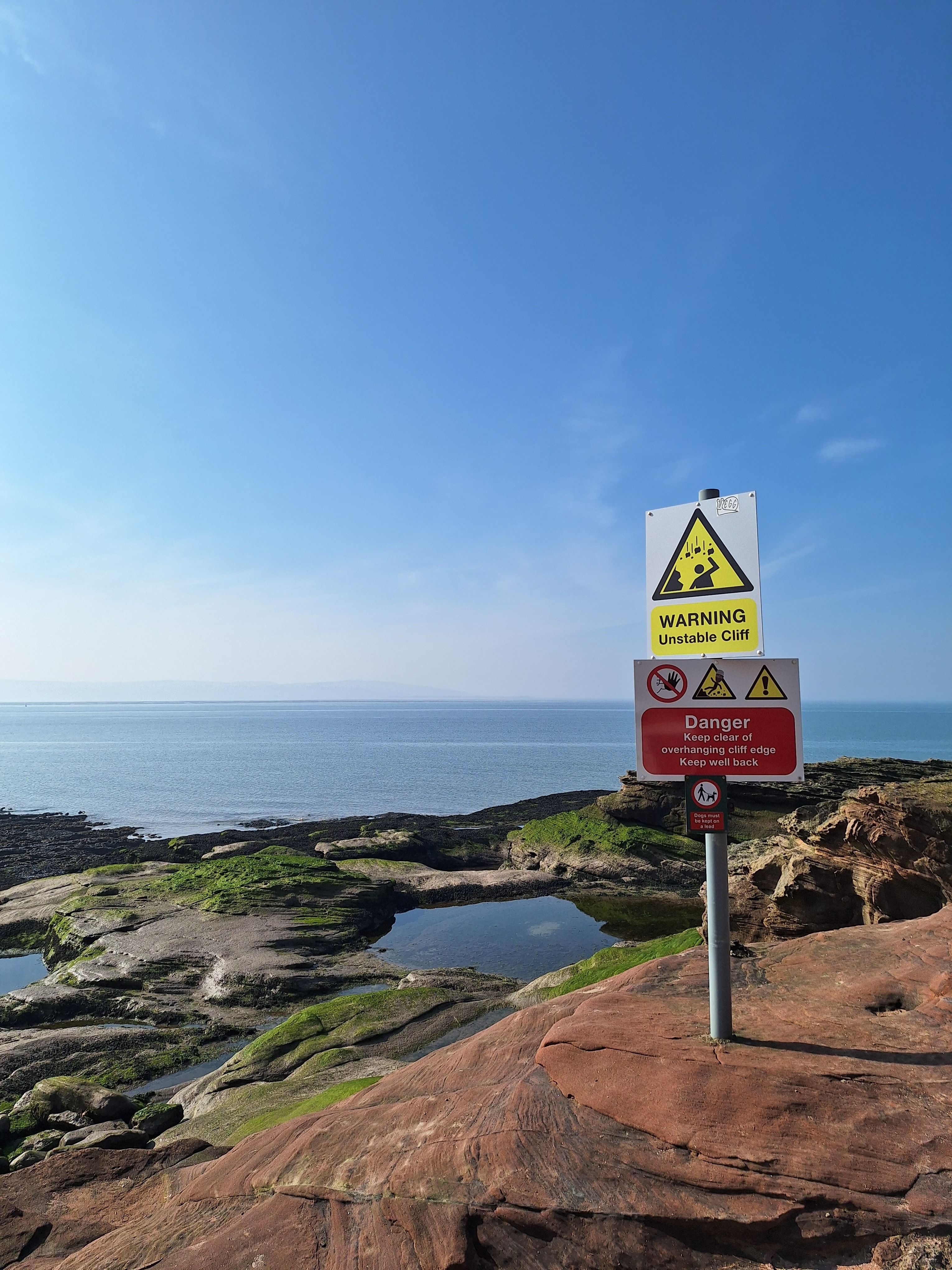 Warning Sign Overlooking Scenic Coastal Cliffs · Free Stock Photo