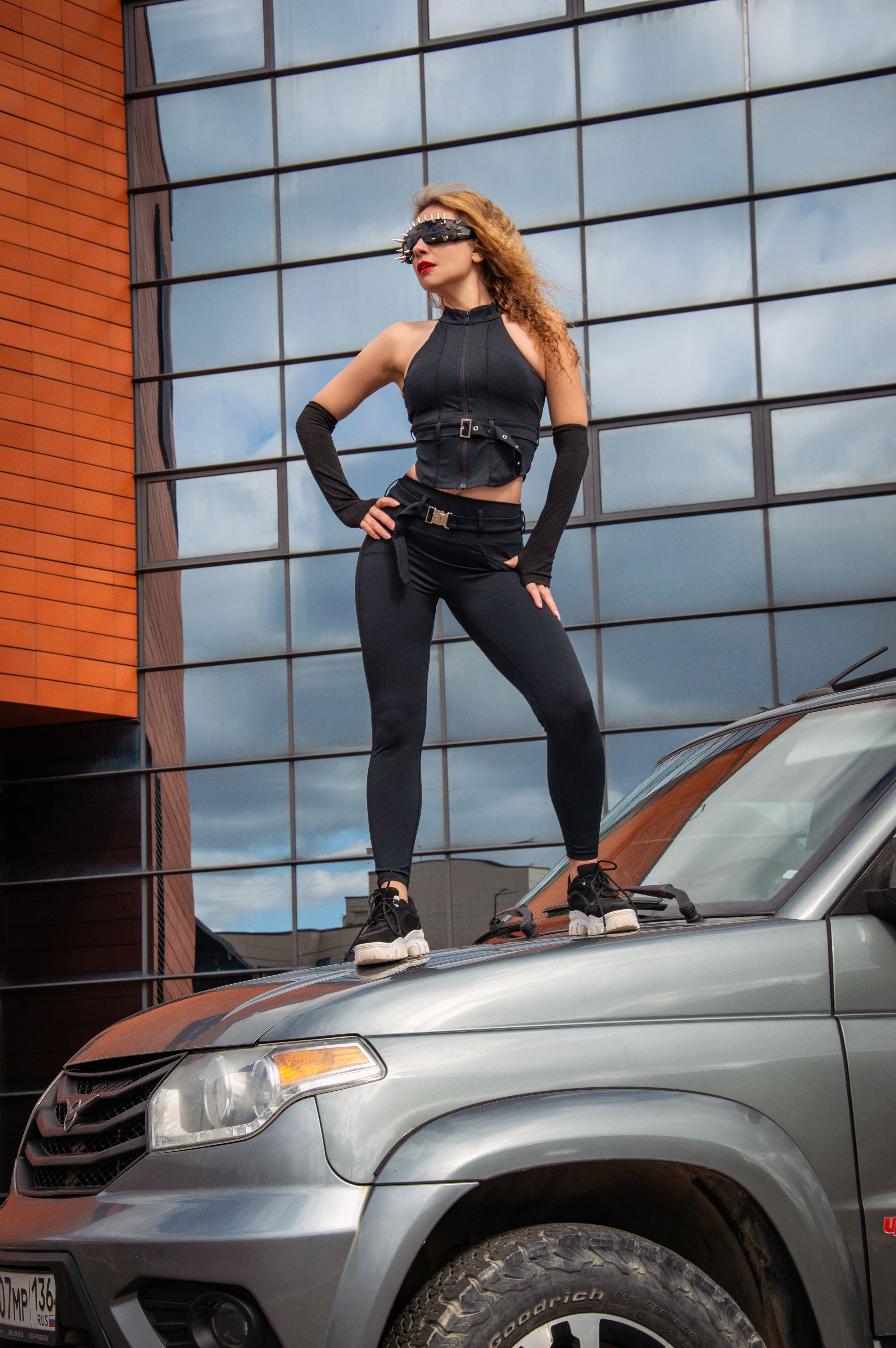 Confident Woman Standing on SUV with Reflective Building · Free Stock Photo