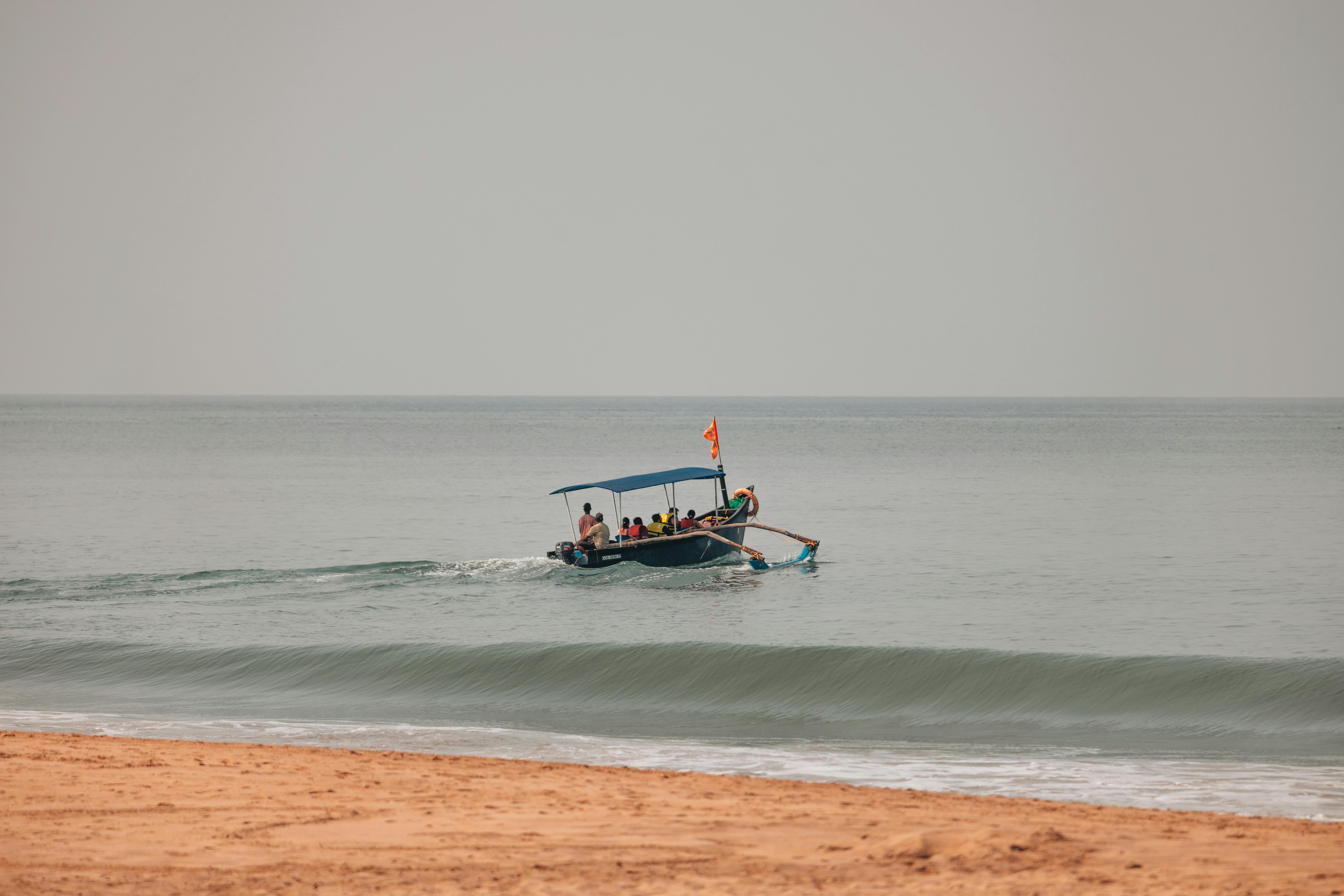 Serene Beach Scene with Fishing Boat at Sea · Free Stock Photo