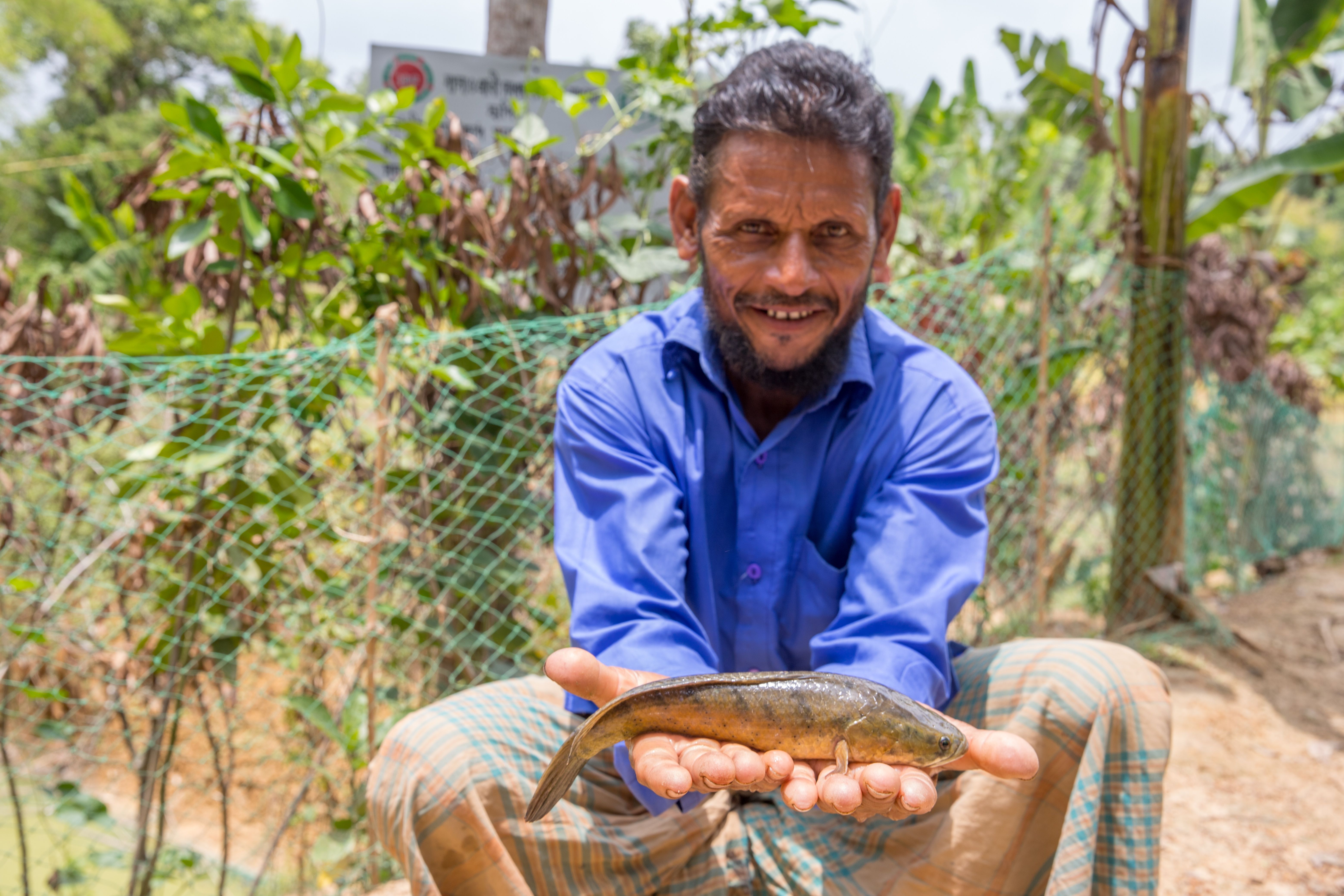 Smiling Man Showing Freshly Caught Fish Outdoors · Free Stock Photo