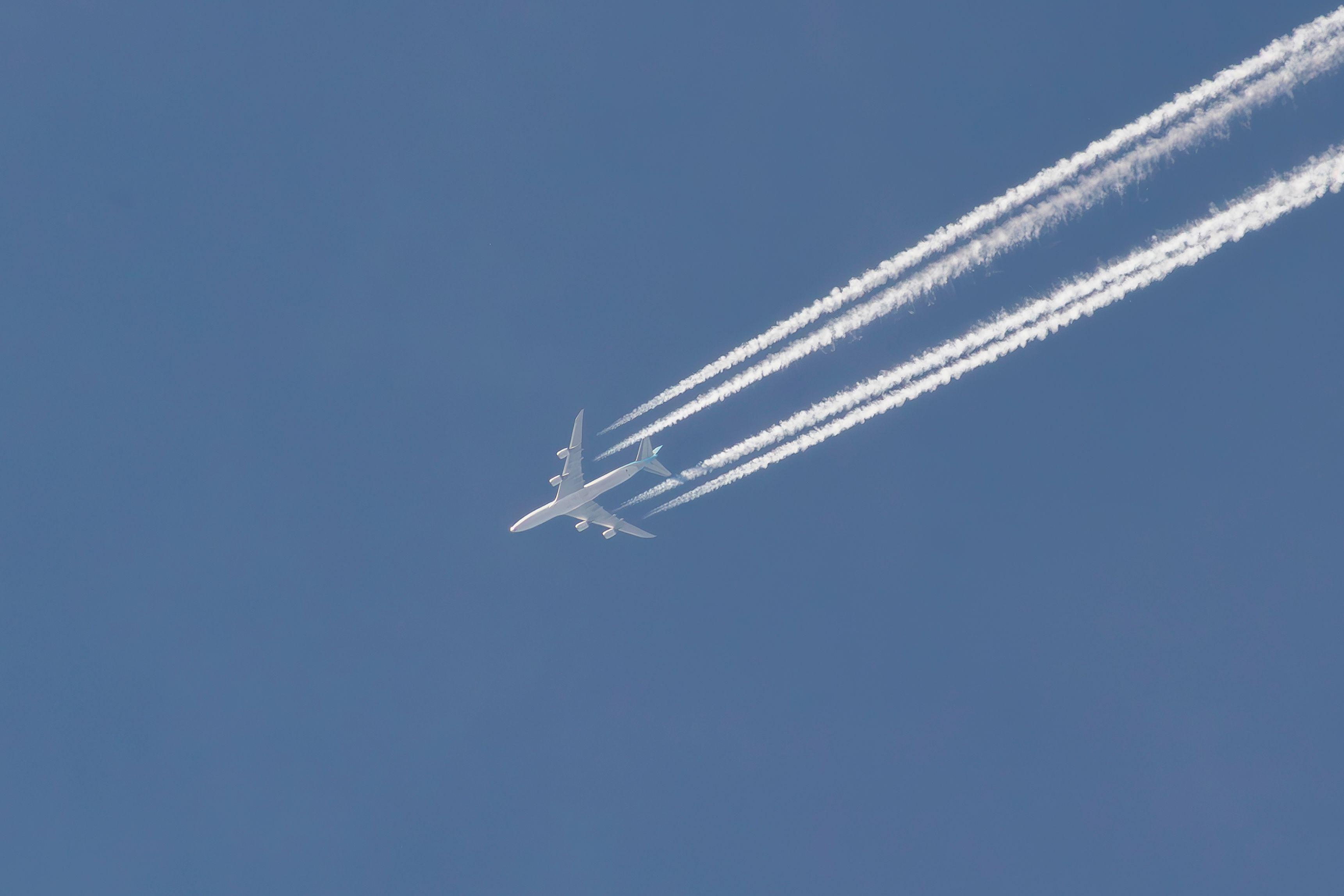 Airplane flying high with contrails in blue sky · Free Stock Photo