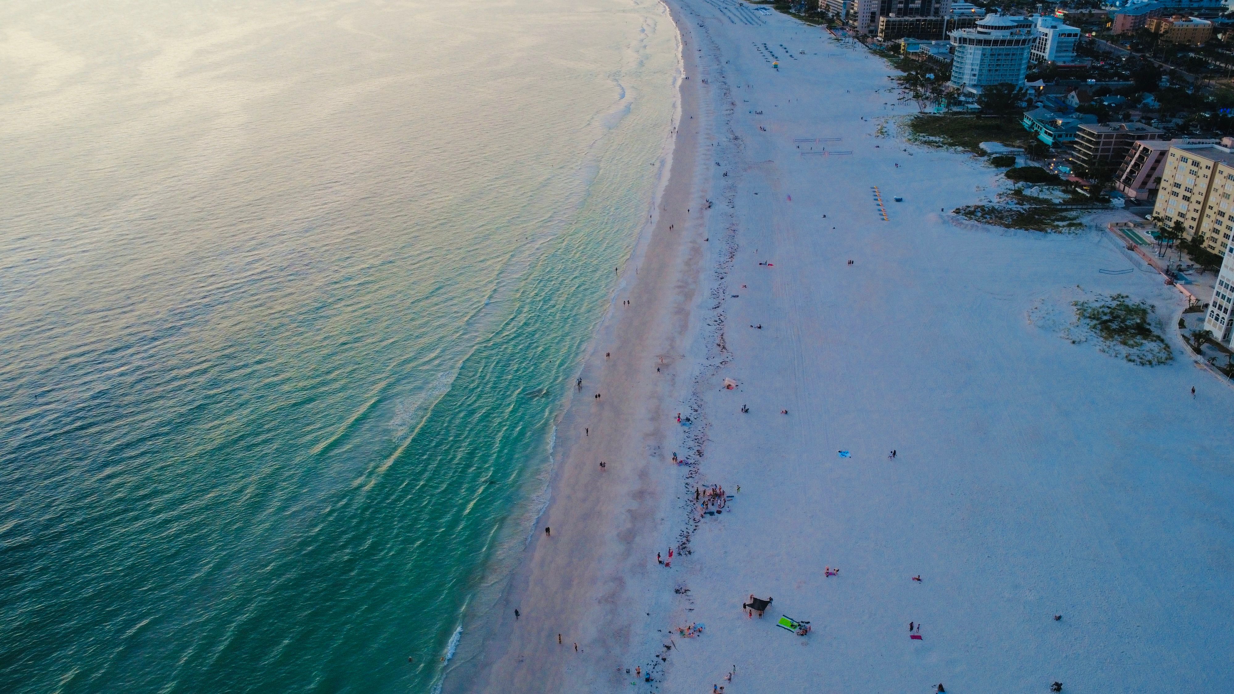 Aerial View of Beachfront at Sunset with Cityscape · Free Stock Photo