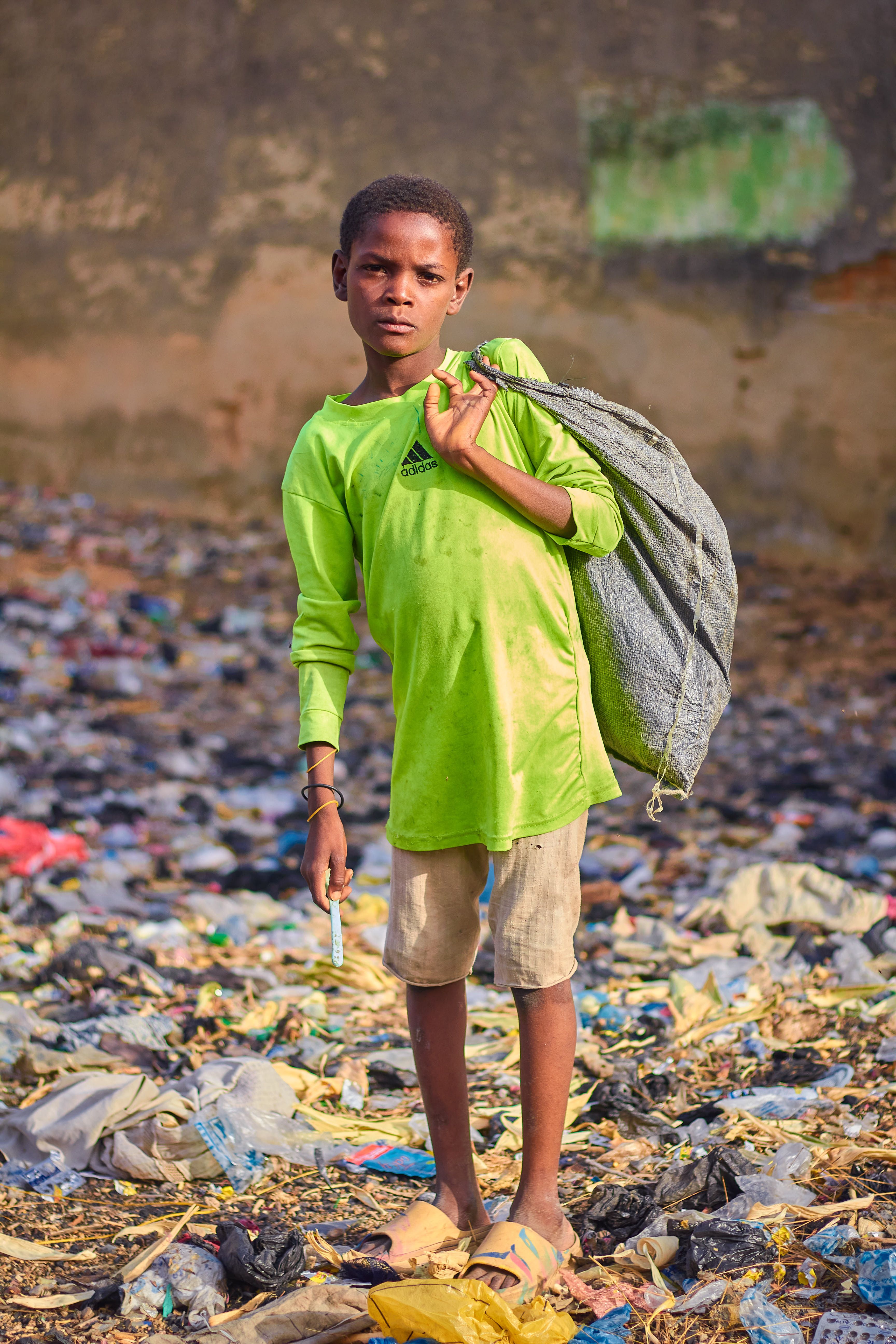 Child Standing in Garbage with Bag and Pen · Free Stock Photo