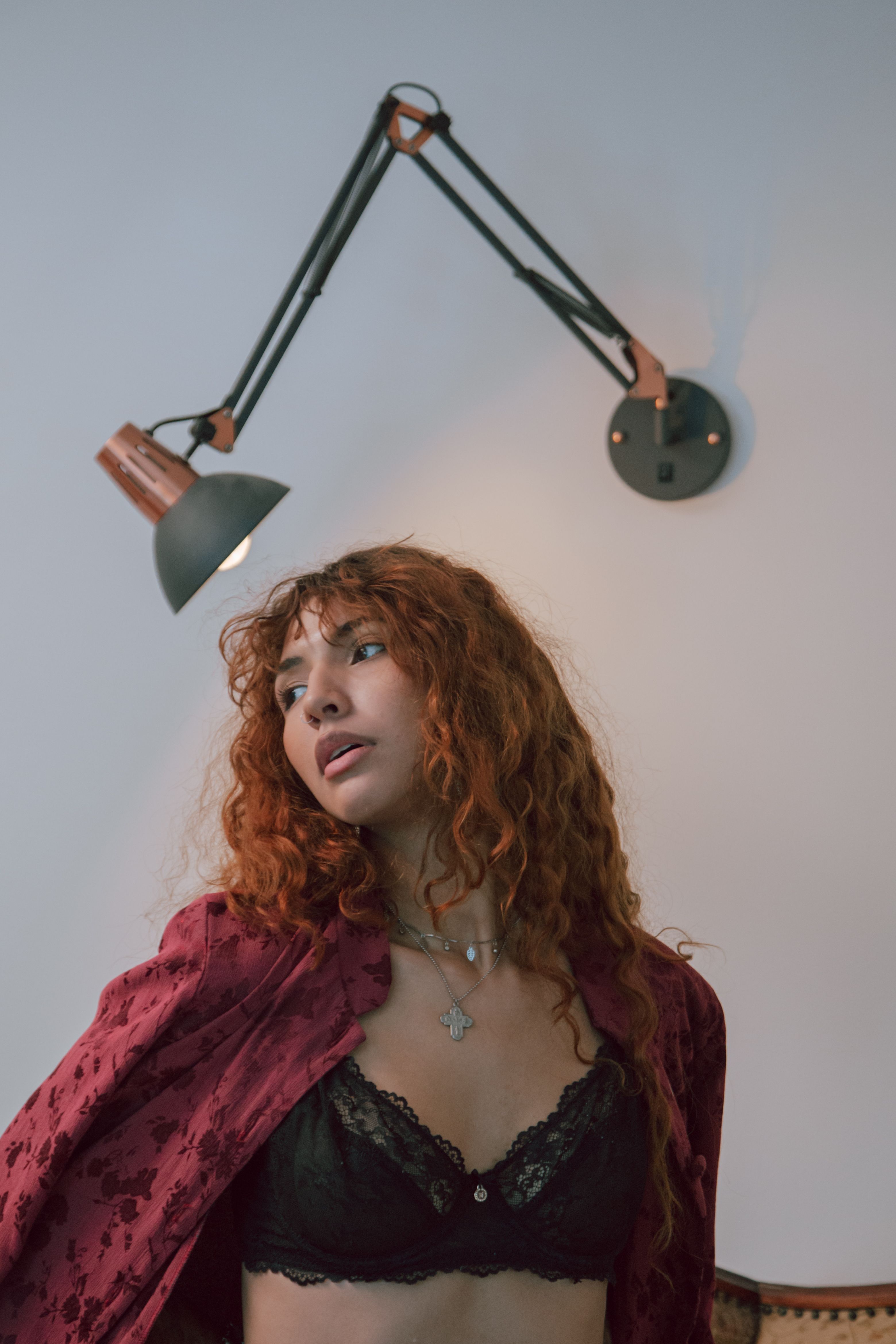 Stylish Woman Posing Indoors with Wall Lamp · Free Stock Photo
