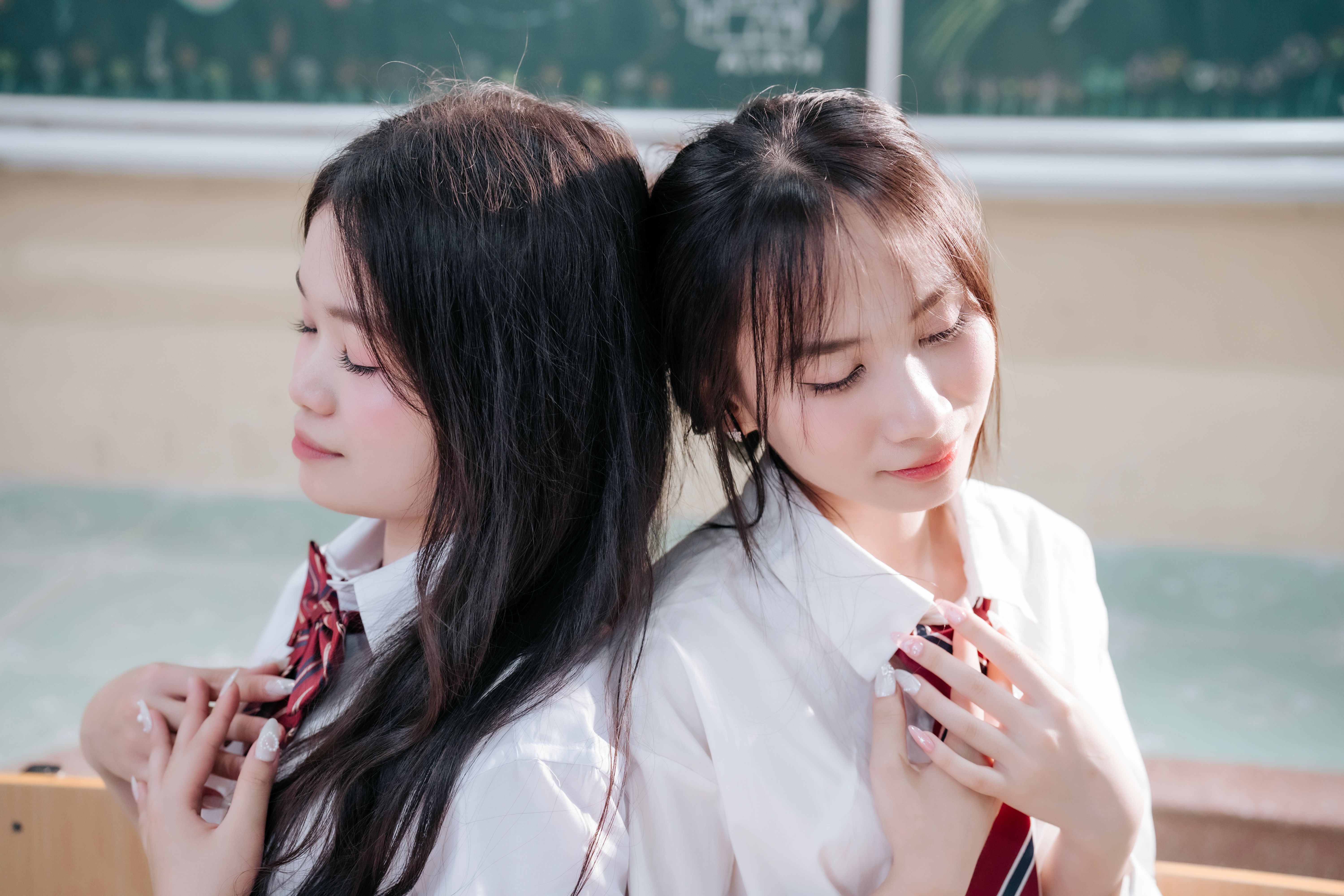 Two Students Leaning Back to Back Smiling · Free Stock Photo