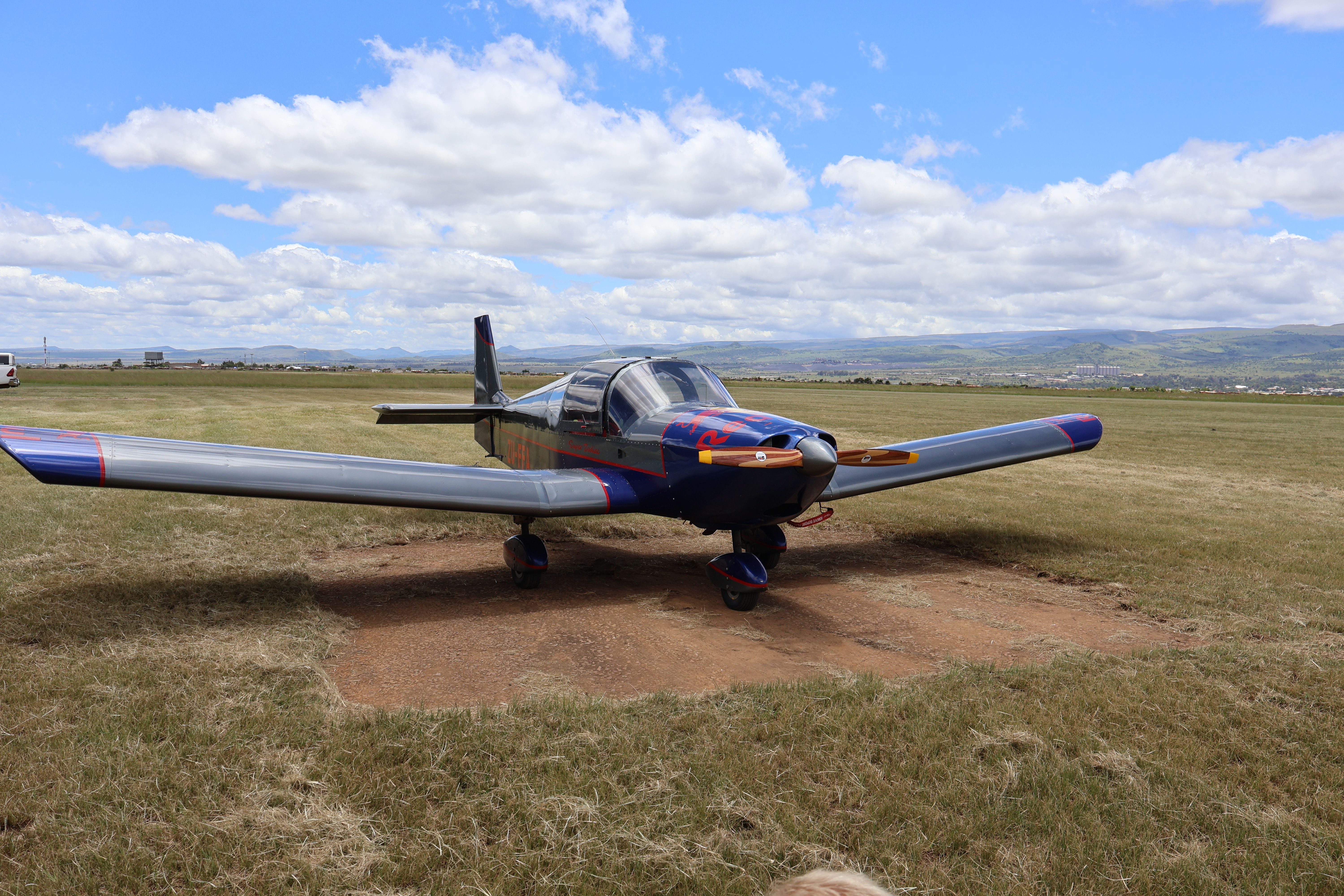 Small Airplane on Grassy Airfield Under Blue Sky · Free Stock Photo