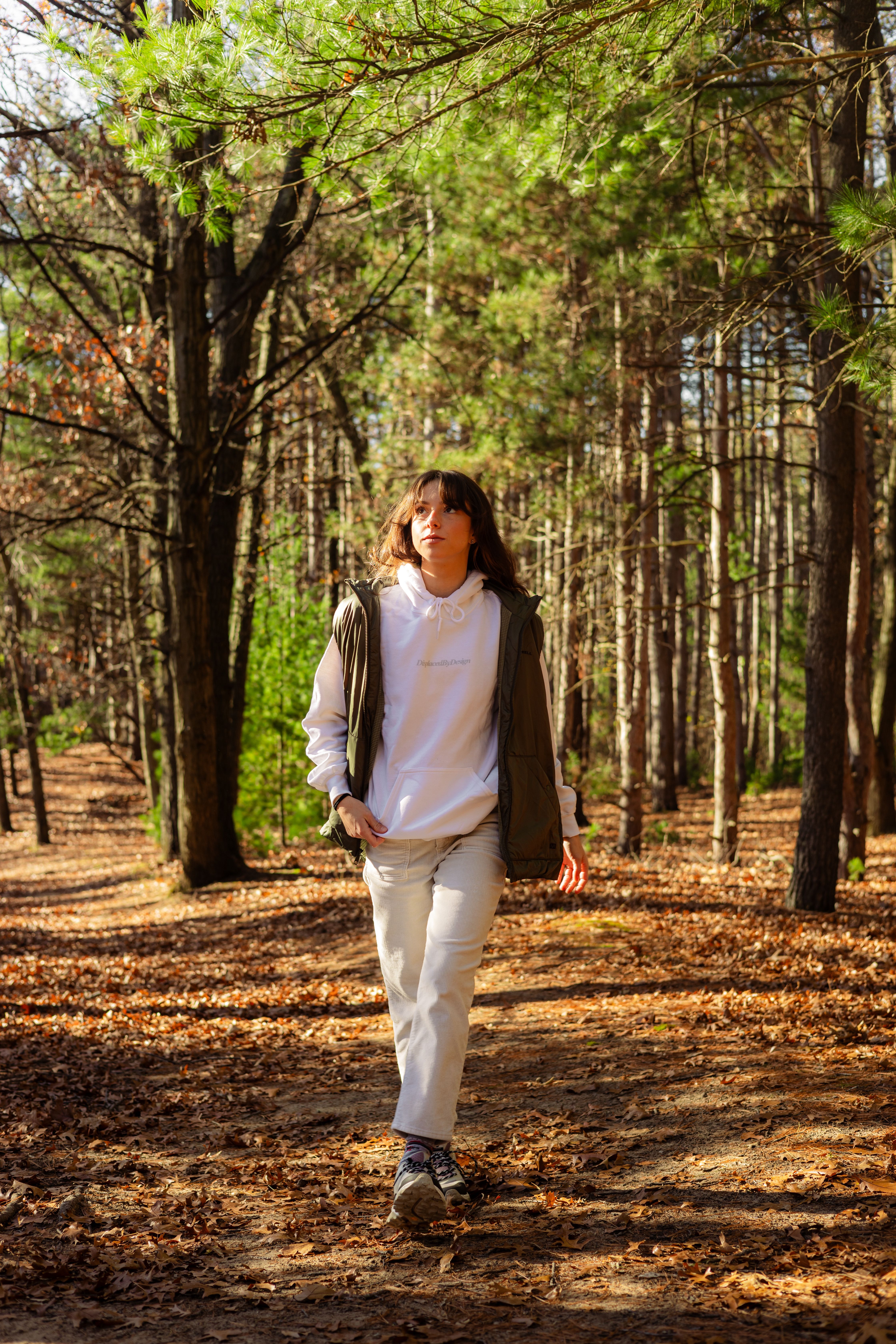 Young person walking through autumn forest path · Free Stock Photo