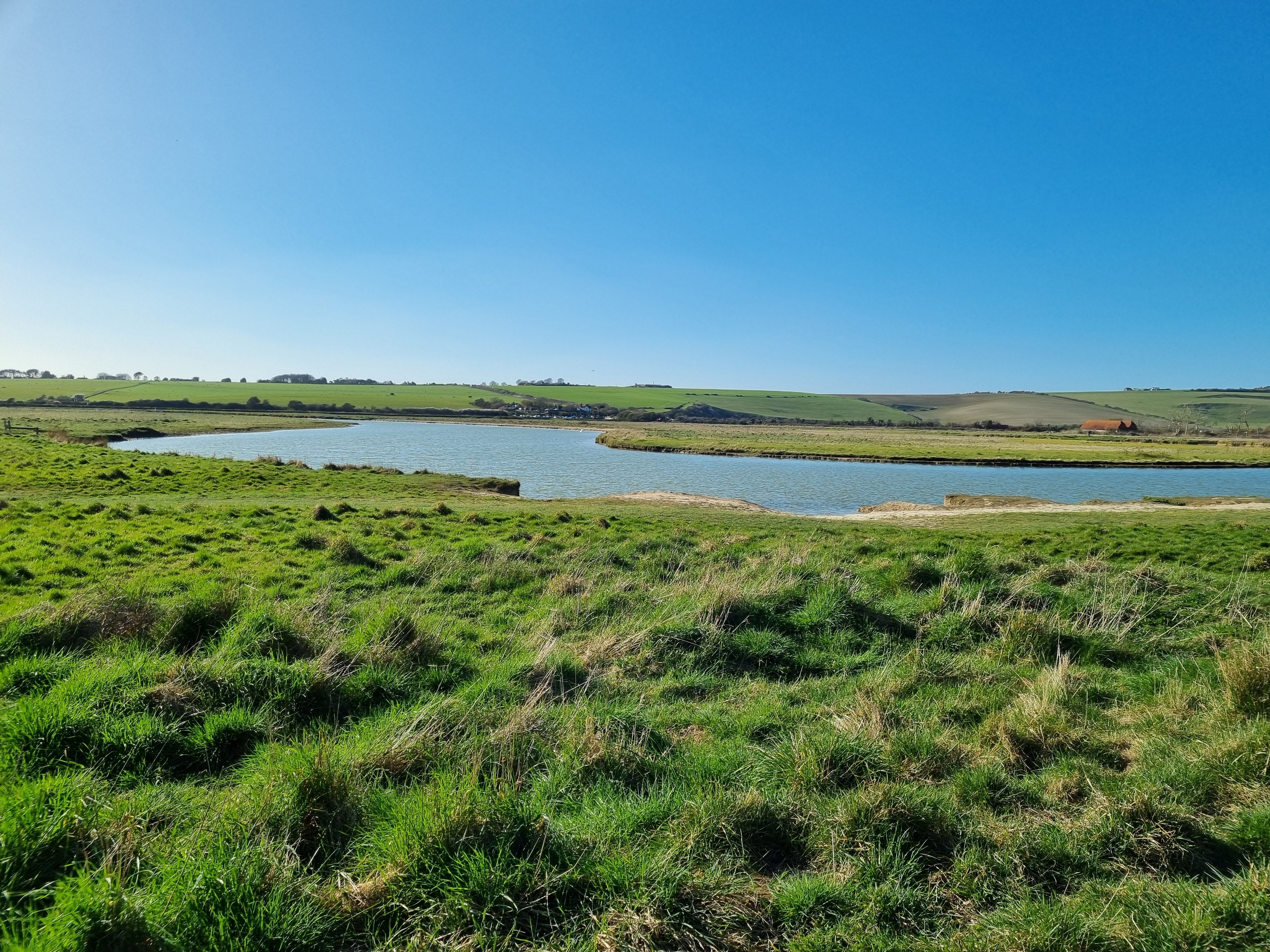 Scenic Riverside Landscape Under Bright Blue Sky · Free Stock Photo