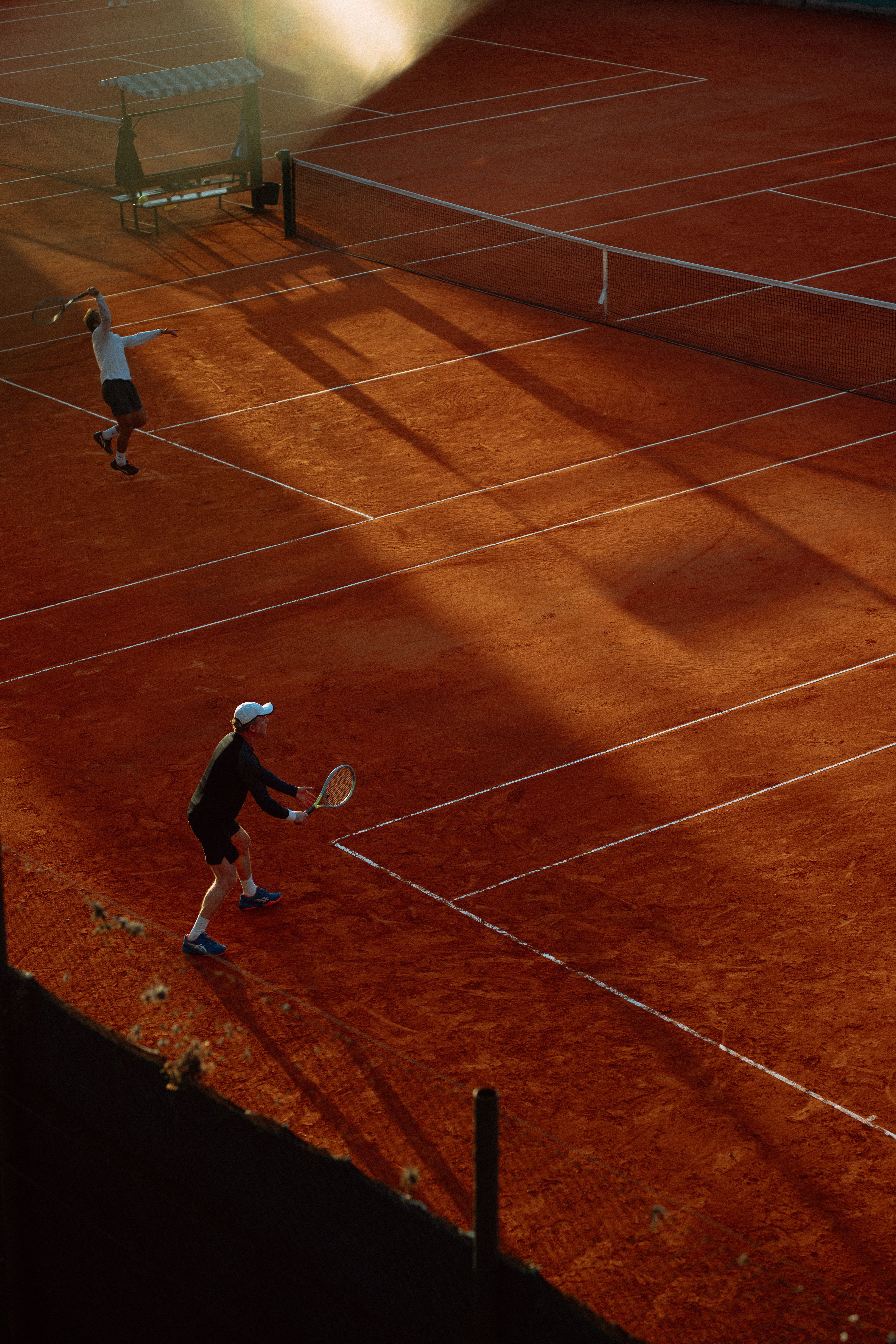 Intense Tennis Match on Clay Court at Sunset · Free Stock Photo