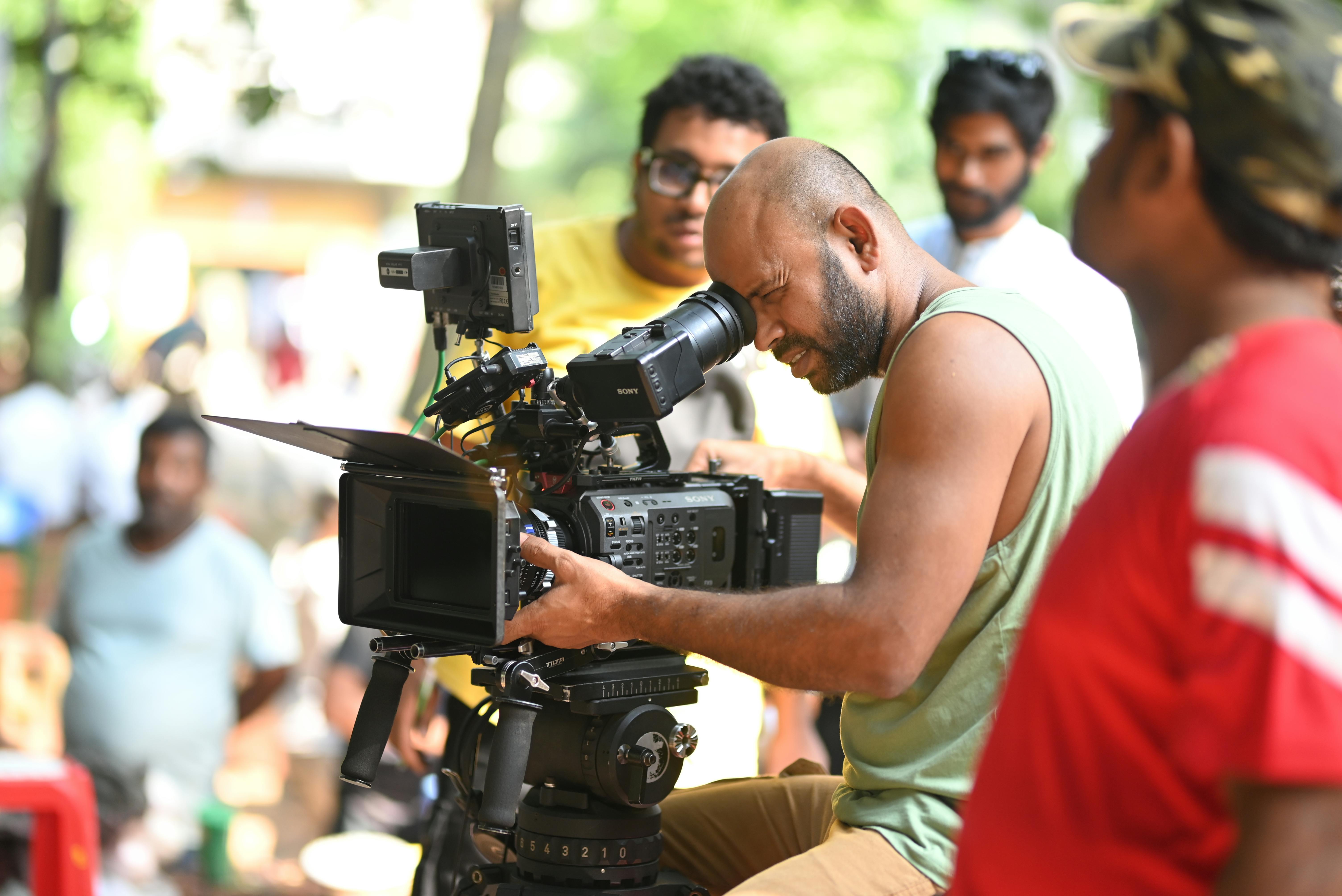 Filmmaker Operating Camera on Outdoor Film Set · Free Stock Photo