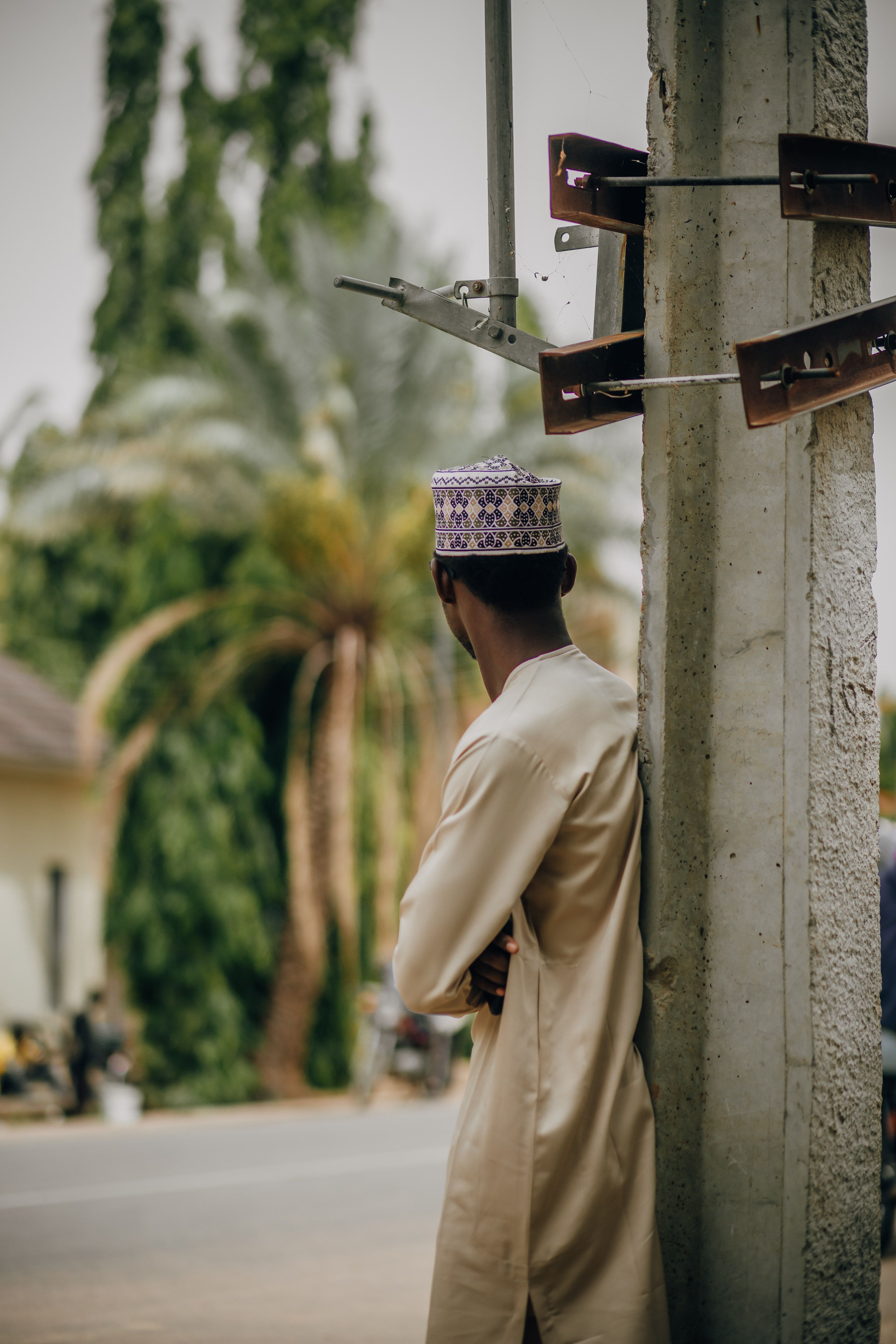 Man in Traditional Attire Leaning on an Outdoor Post · Free Stock Photo