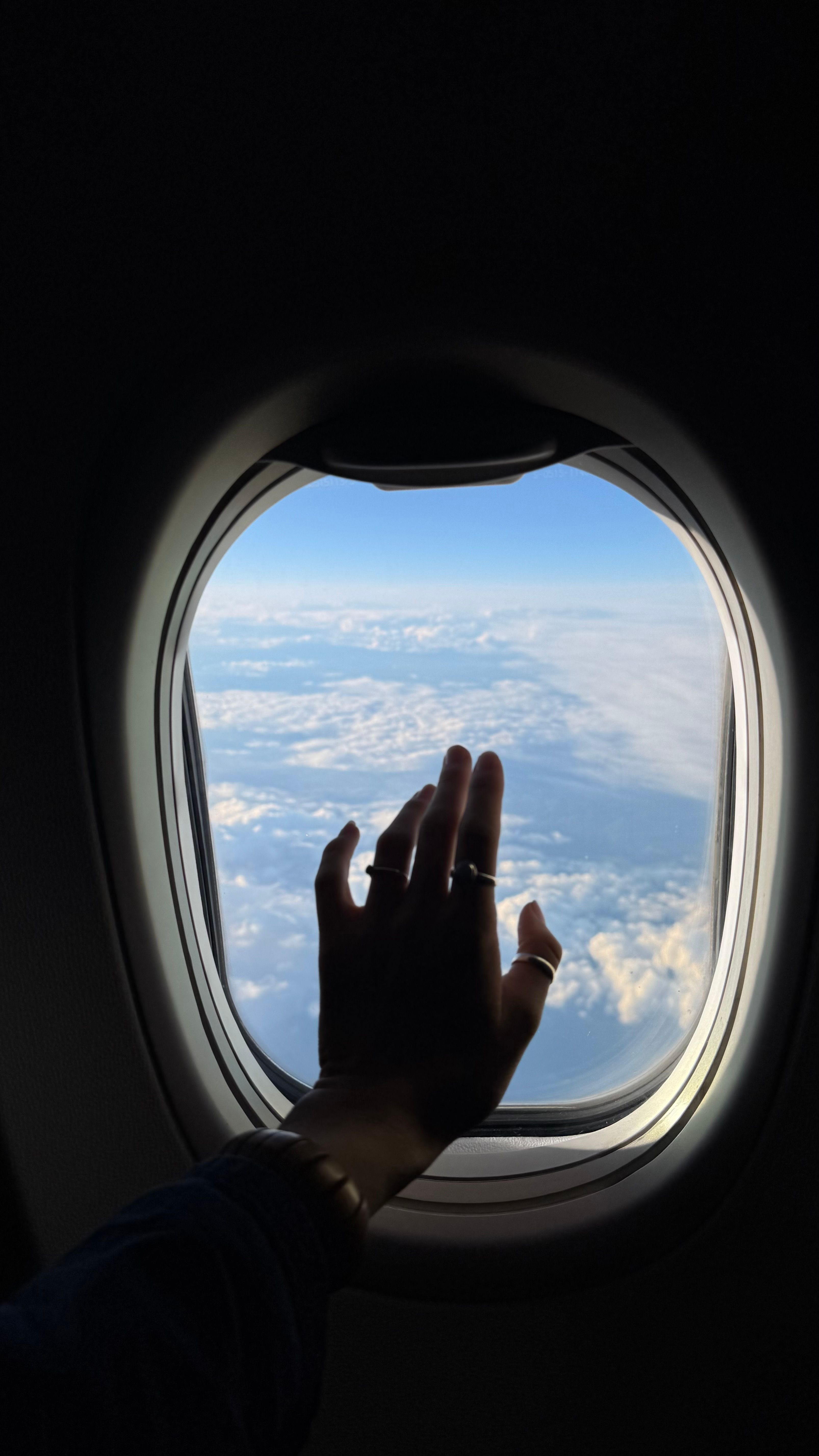 Hand Reaching Through Airplane Window in Flight · Free Stock Photo