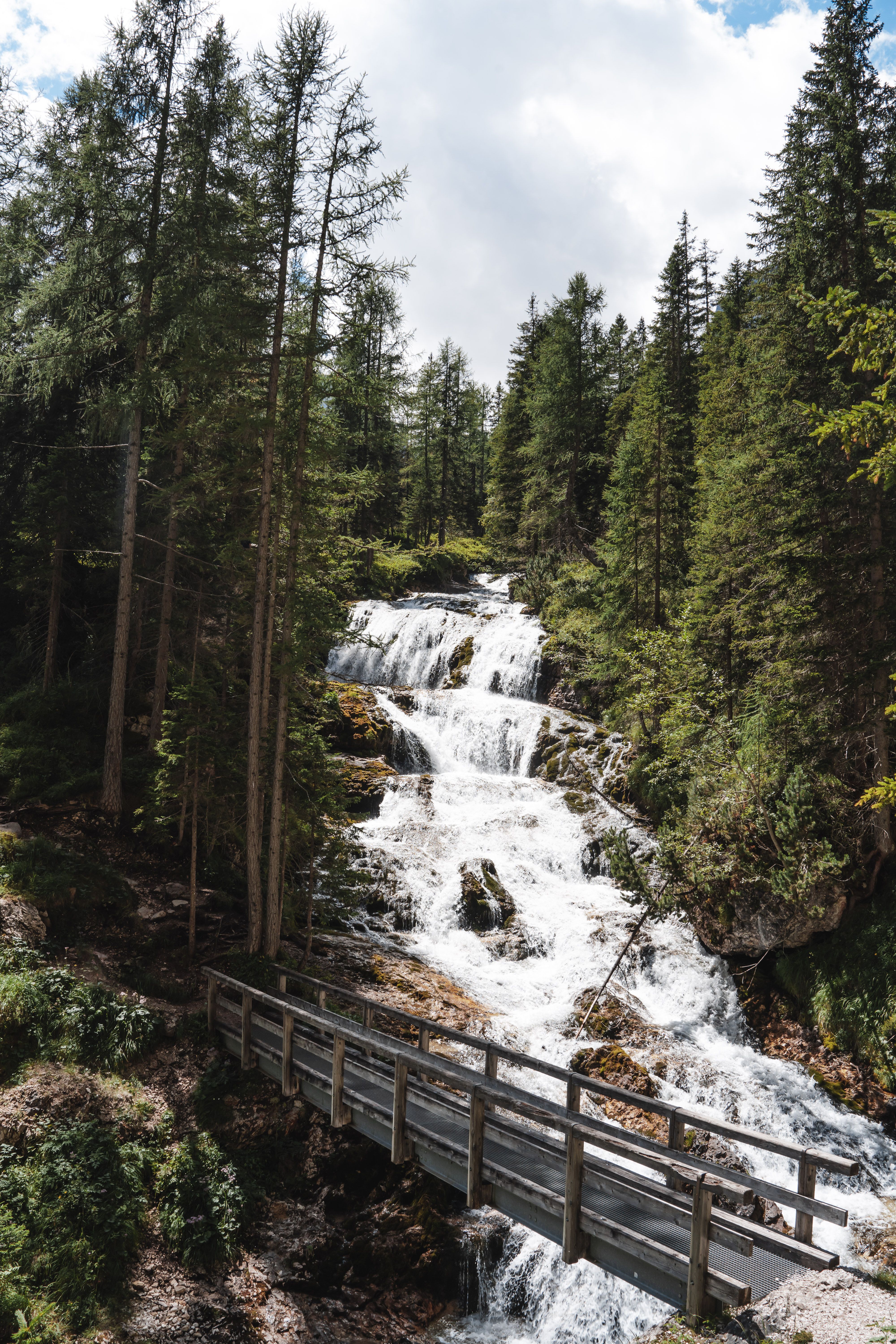 Scenic Waterfall Crossing a Wooden Bridge · Free Stock Photo