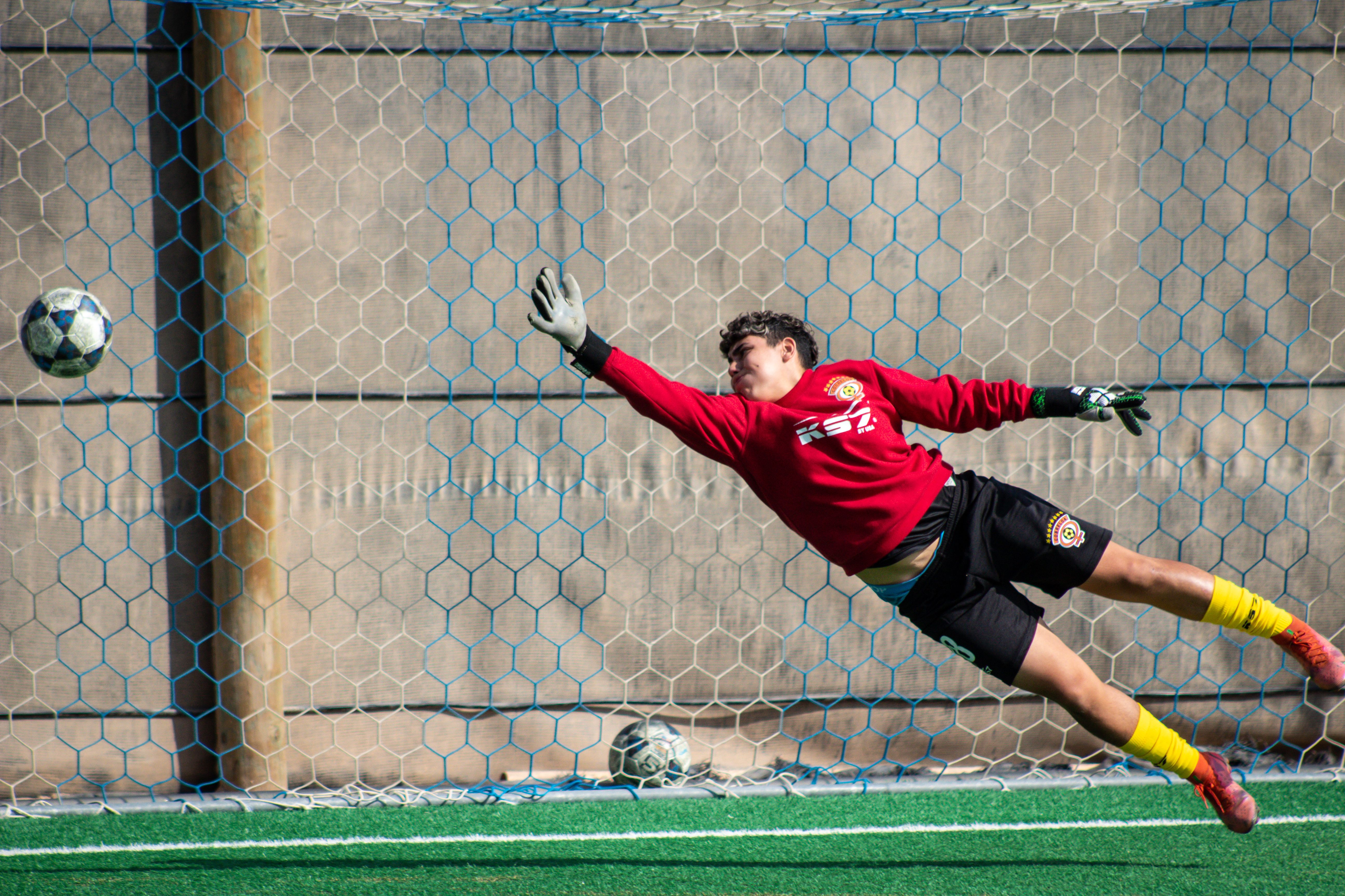 Goalkeeper Leaping to Save Soccer Ball on Field · Free Stock Photo