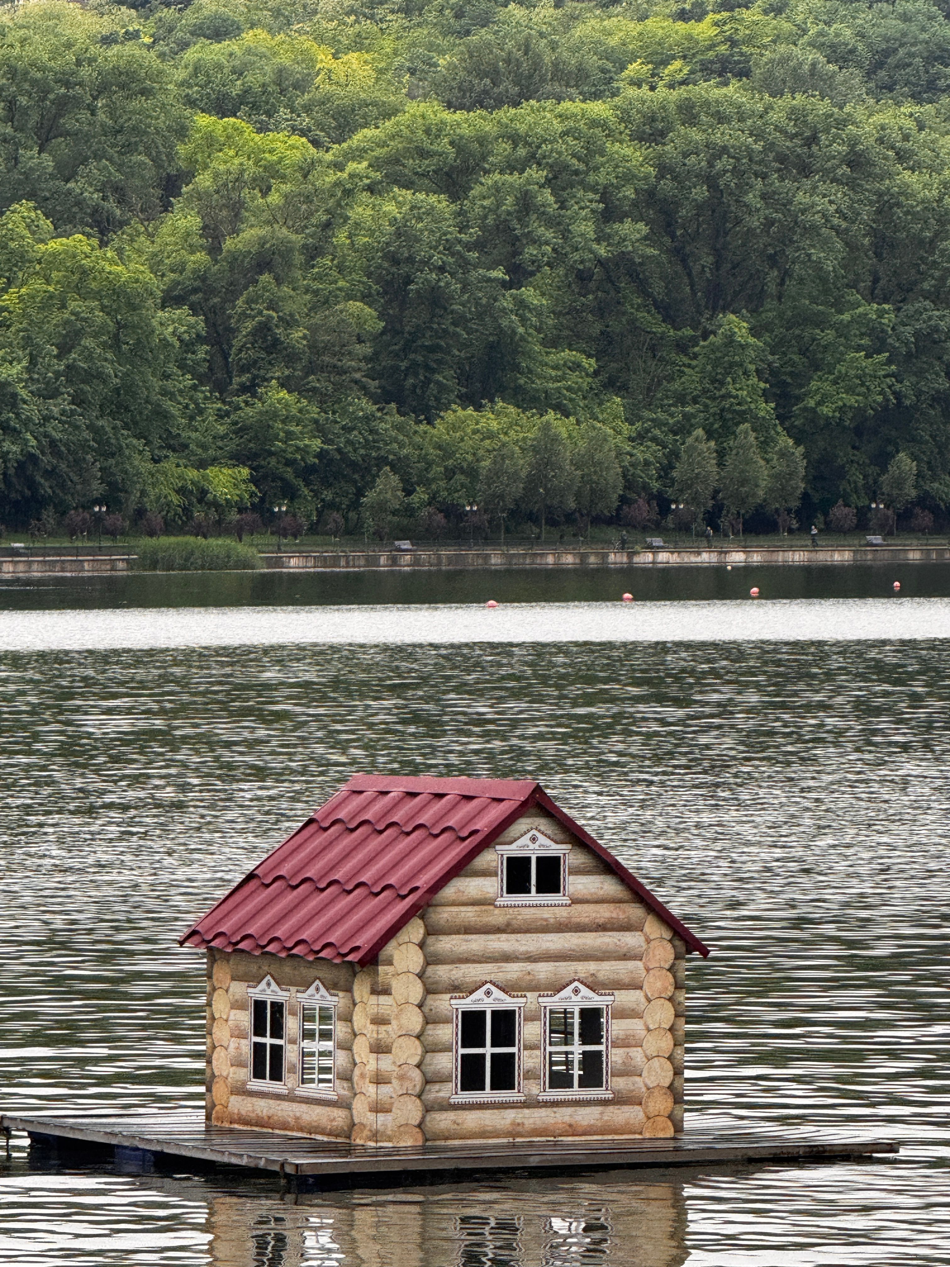 Floating Log Cabin on Serene Lake with Forest Backdrop · Free Stock Photo