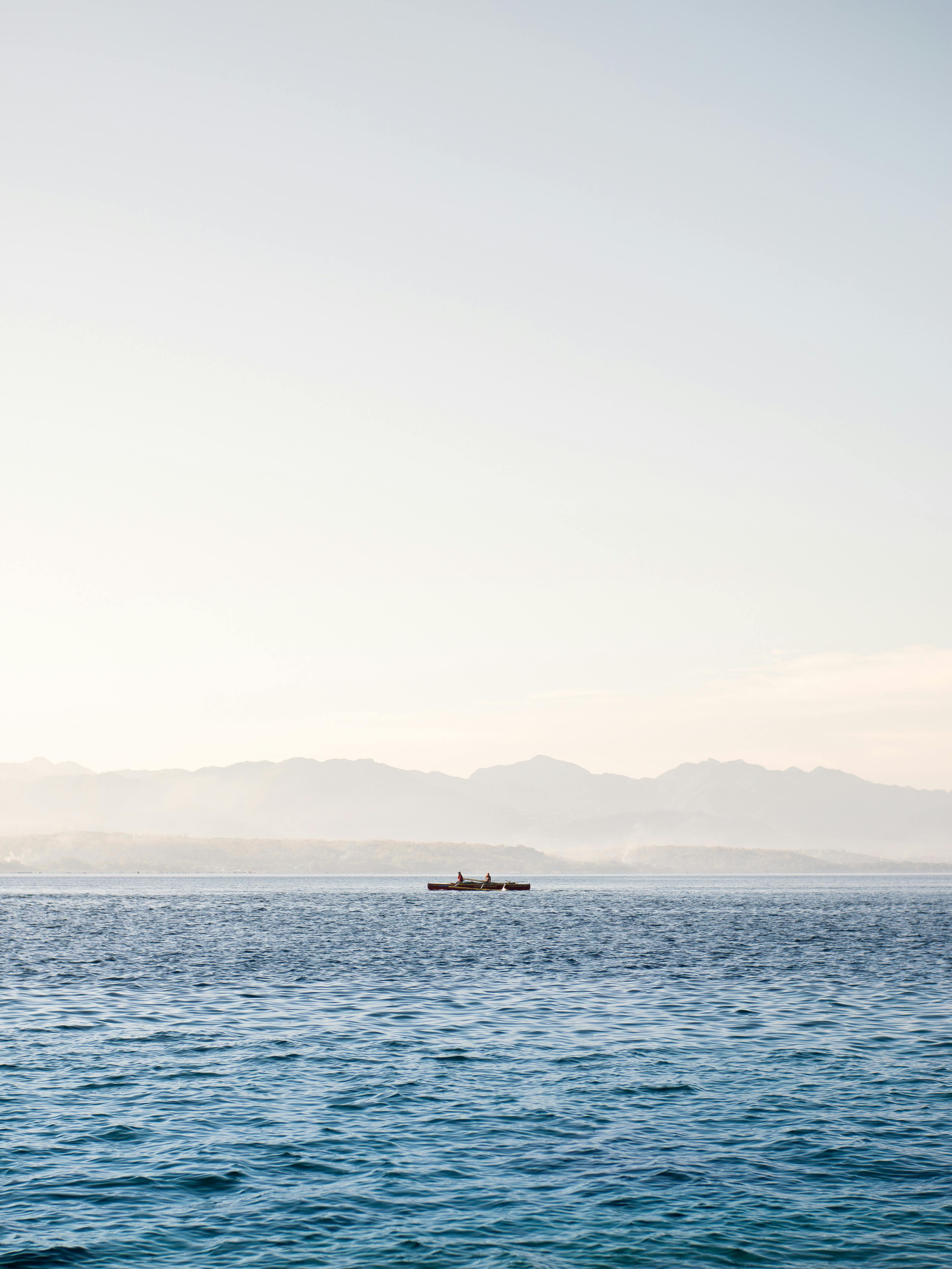 Tranquil Sea with Distant Boat and Mountain View · Free Stock Photo