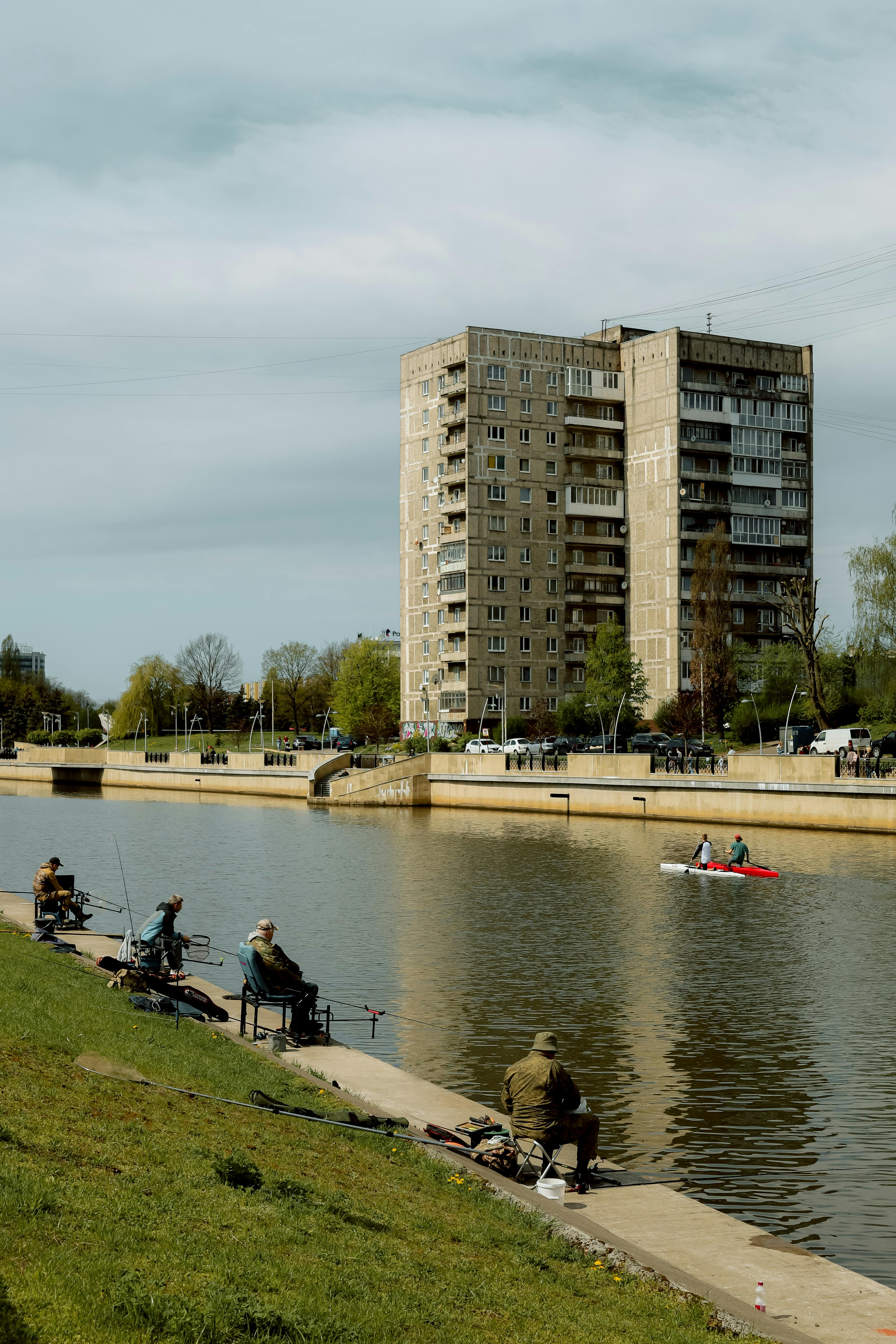 Urban Riverside Scene with Fishermen and Kayakers · Free Stock Photo