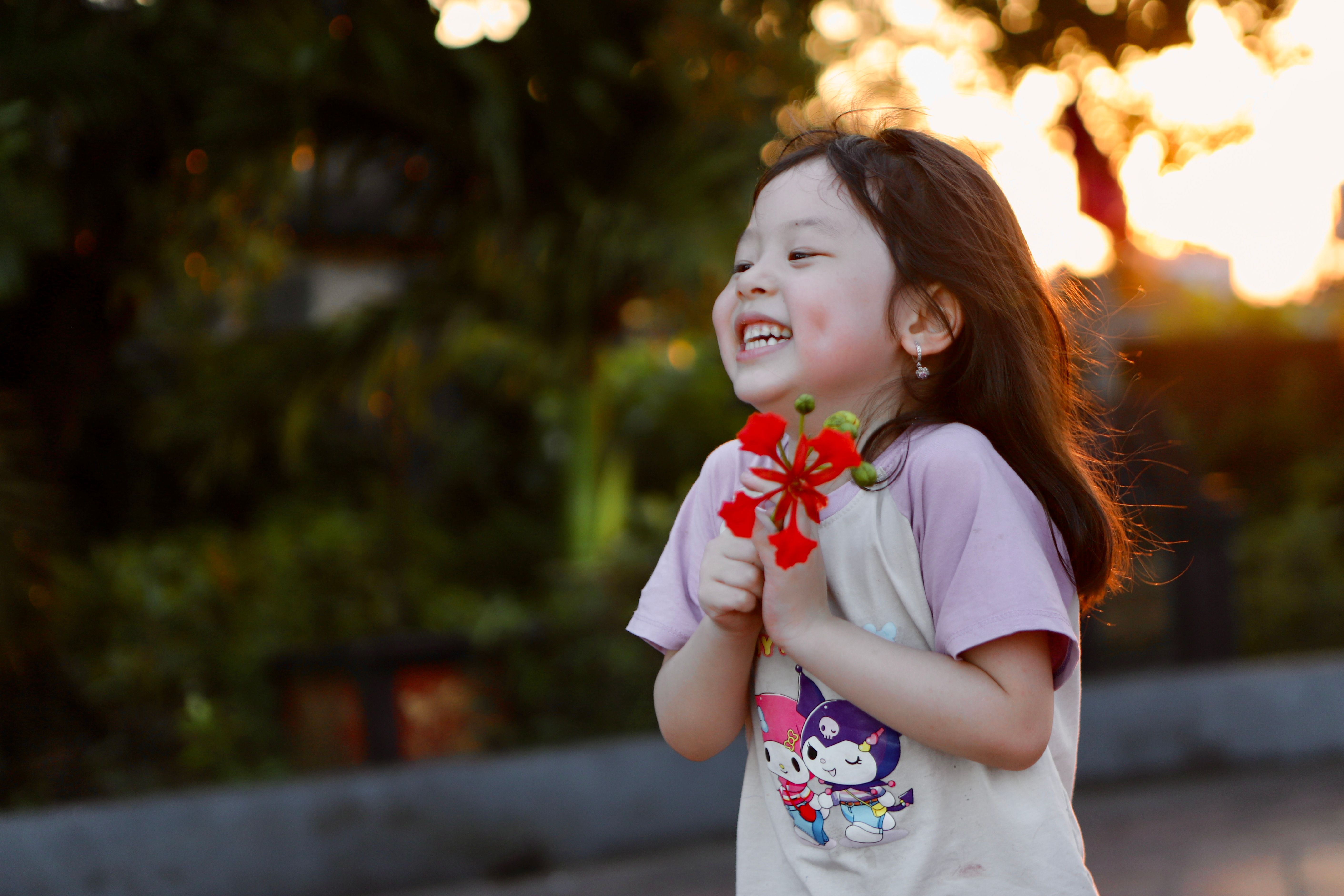 Joyful Child with Crimson Flower at Sunset · Free Stock Photo