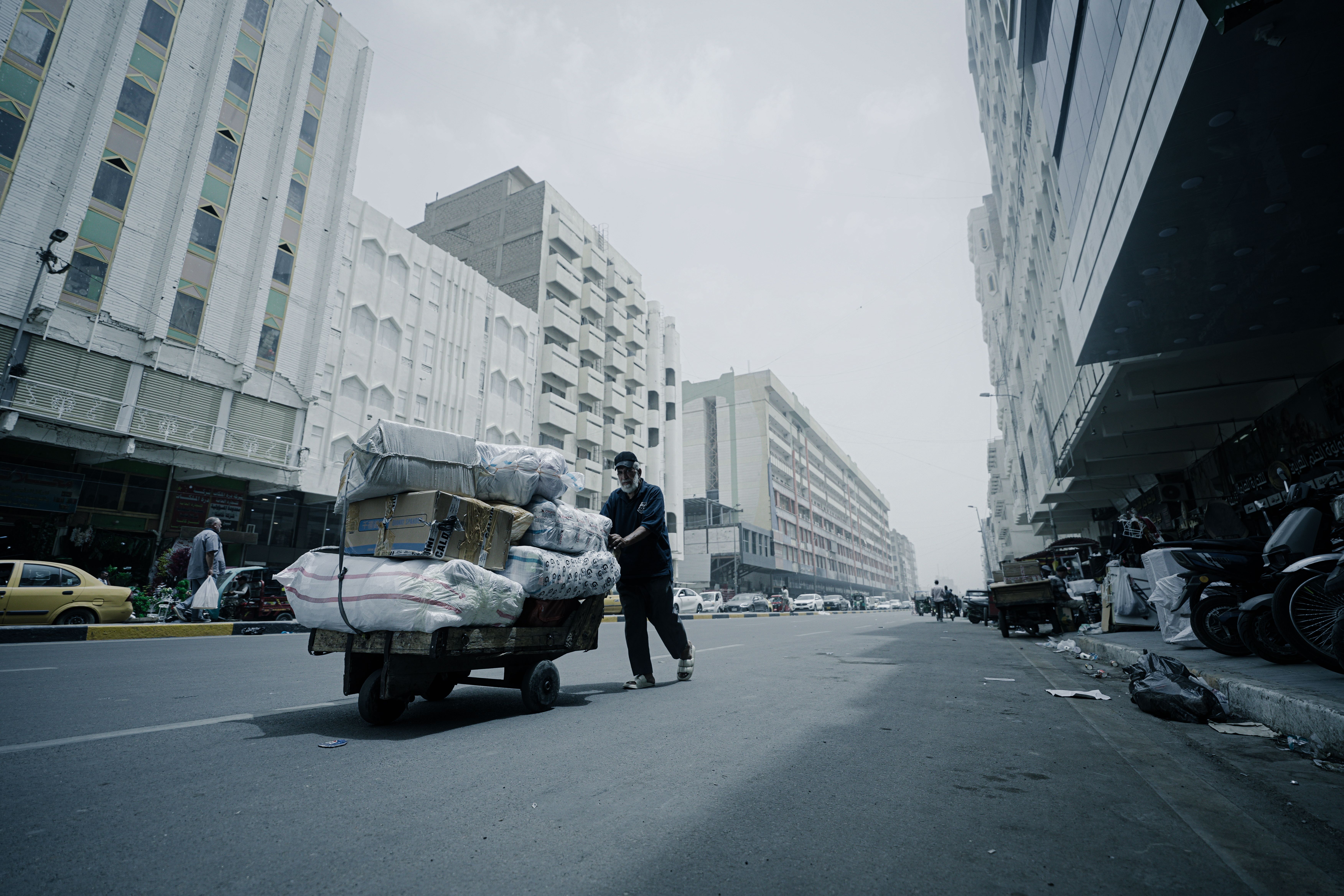 Urban Street Scene with Worker Pushing Cart · Free Stock Photo