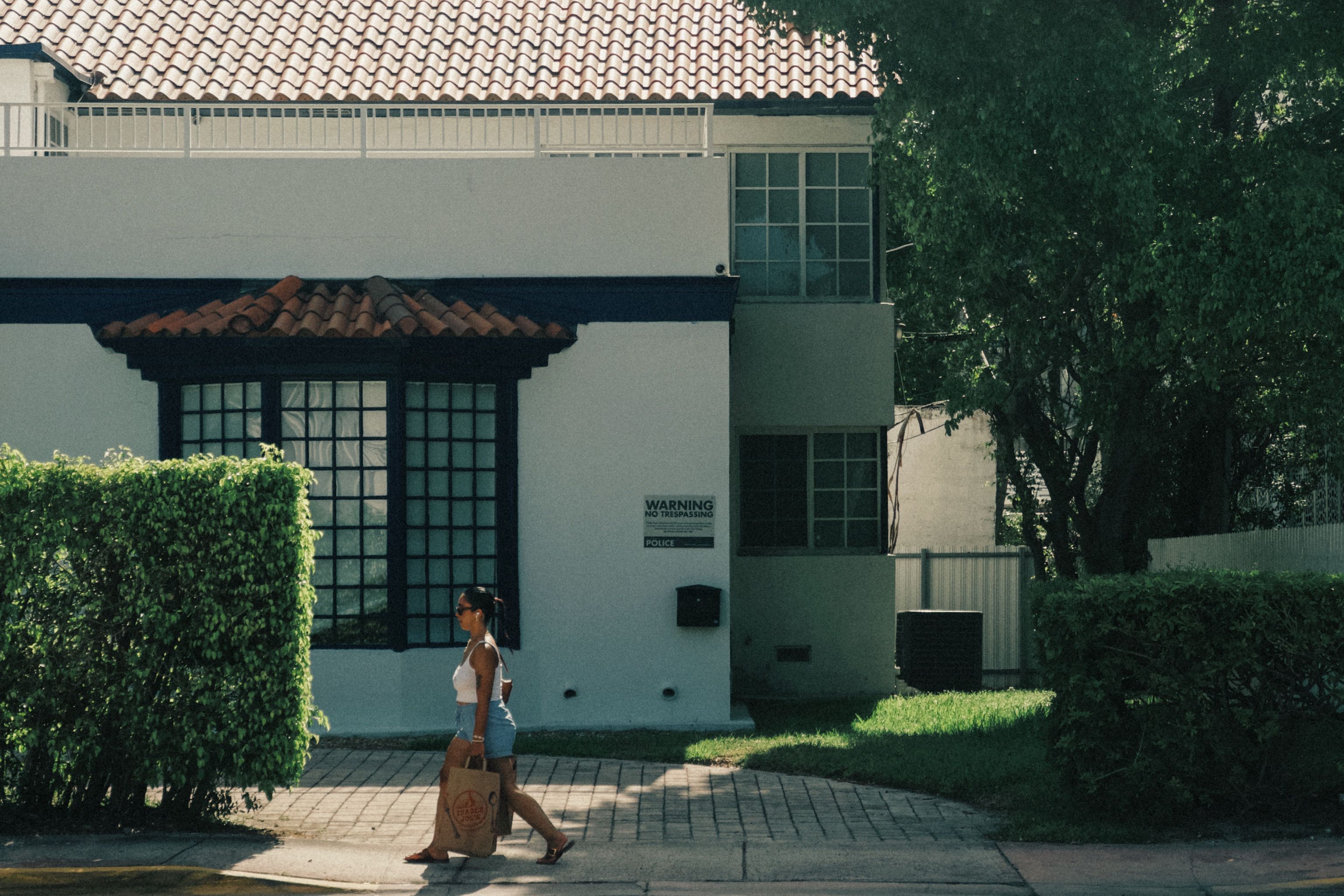 Woman Walking Past a Modern House in Suburban Setting · Free Stock Photo