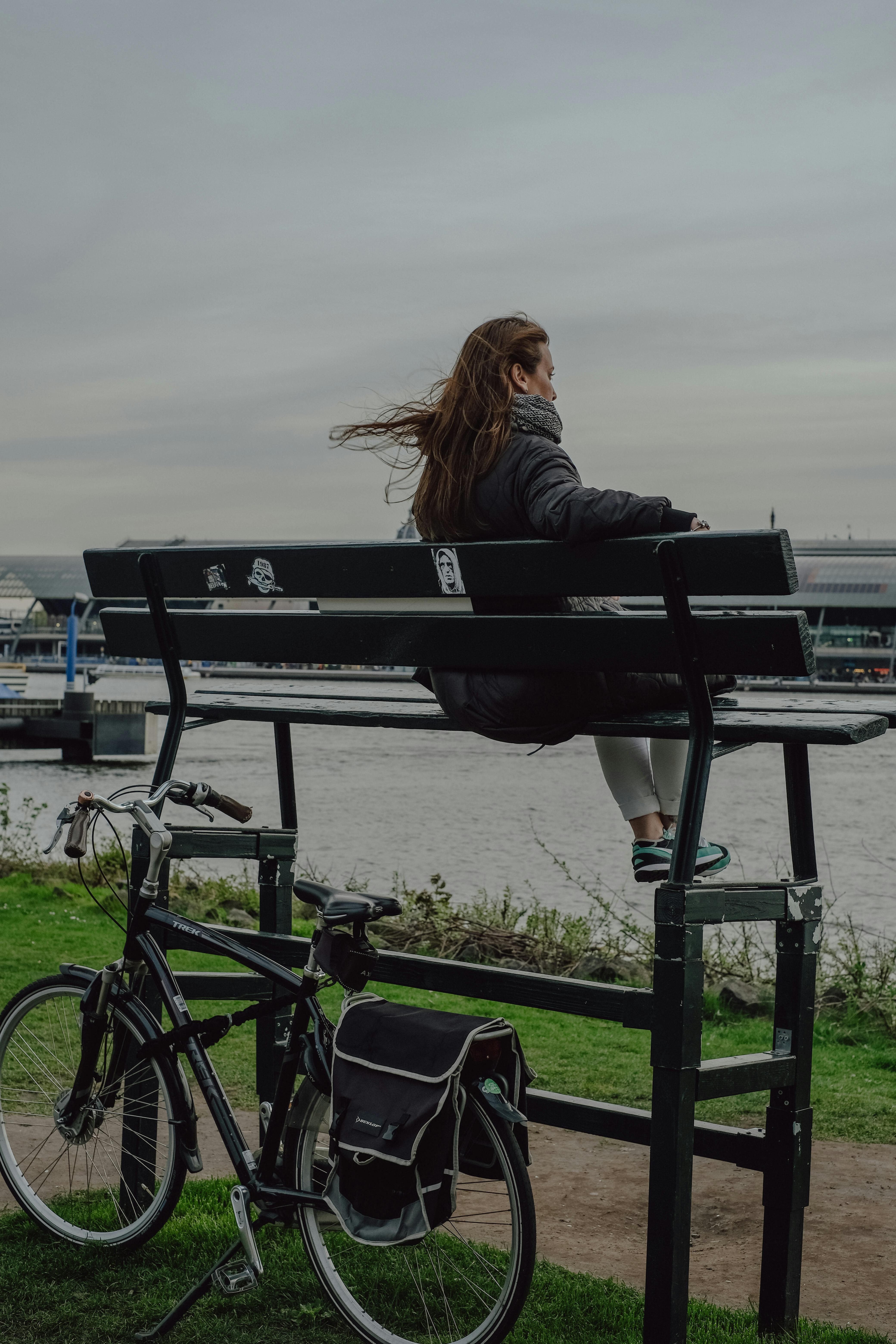 Woman Relaxing on Elevated Bench by River · Free Stock Photo