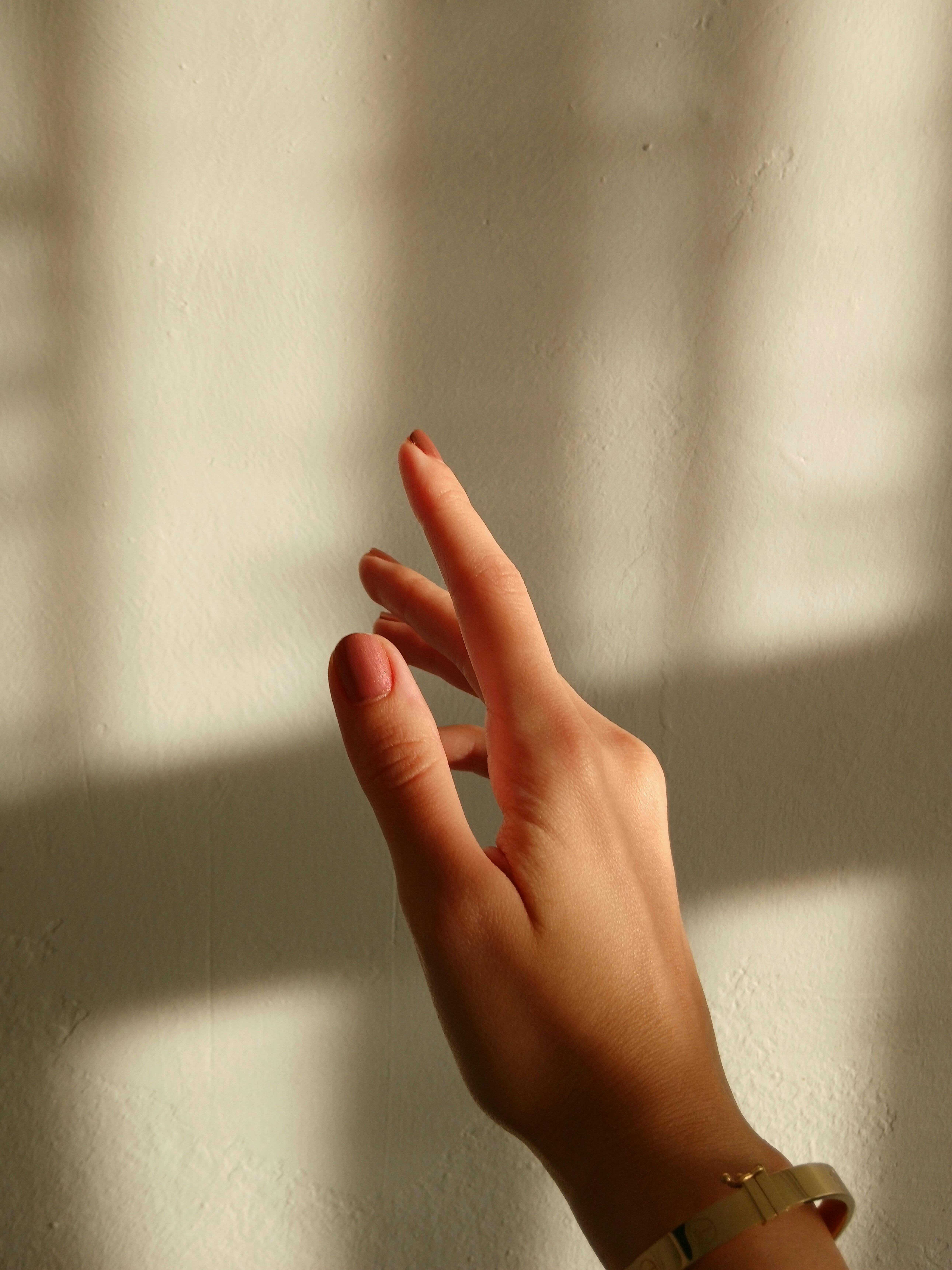 Female hand against wall with shadow · Free Stock Photo