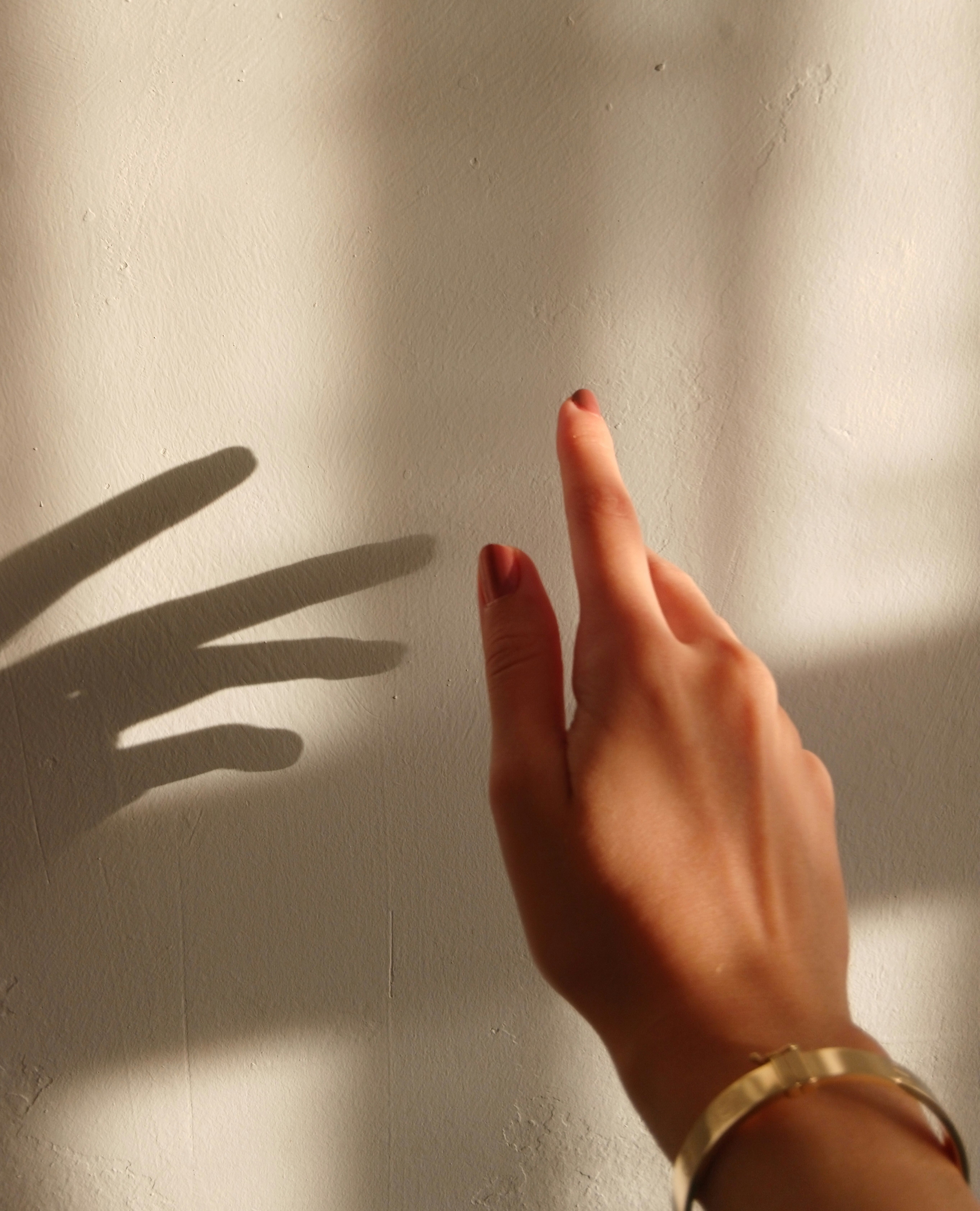 Hand Reaching for Shadow on Sunlit Wall · Free Stock Photo