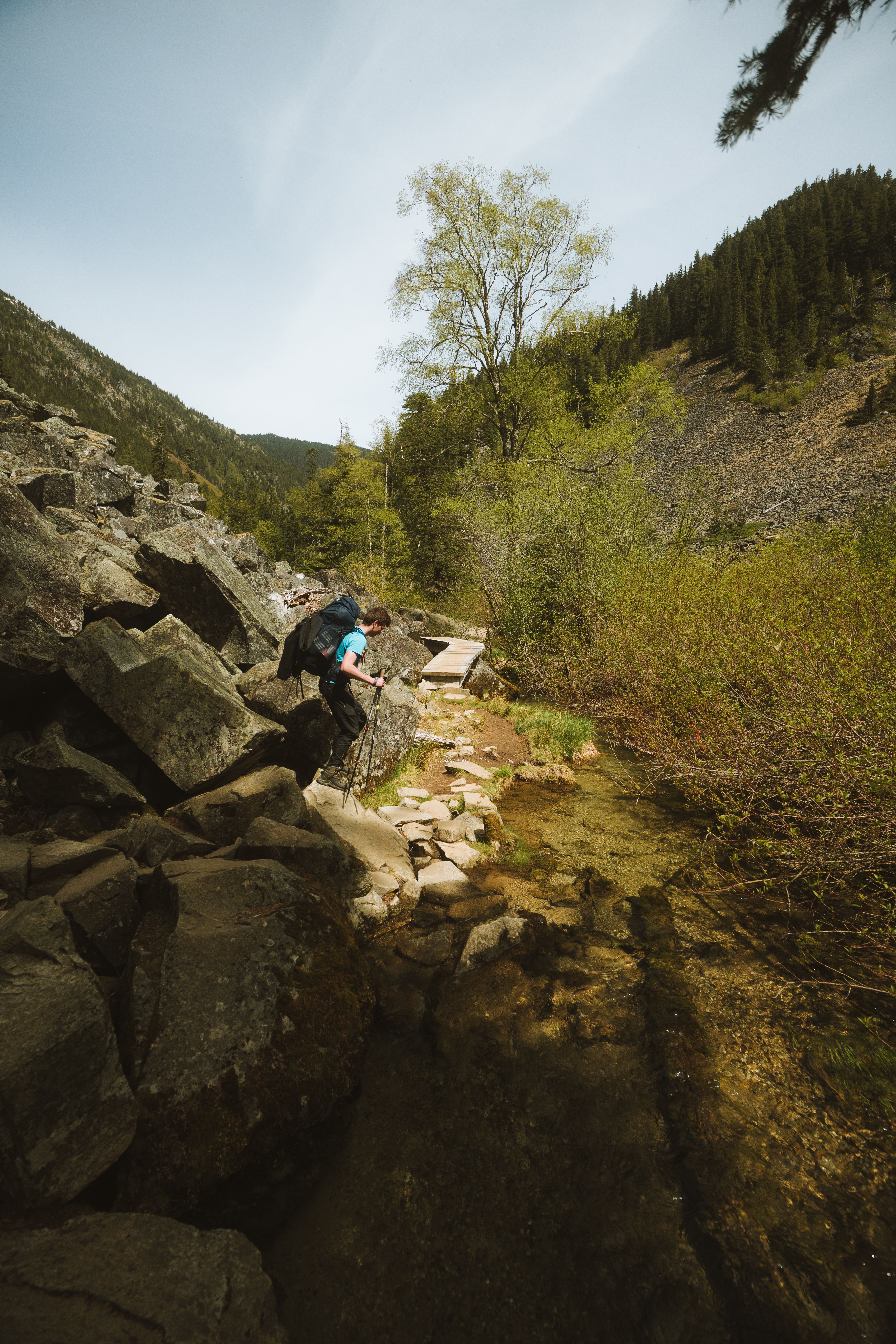 Solo Hiker Crossing Rocky Mountain Stream · Free Stock Photo
