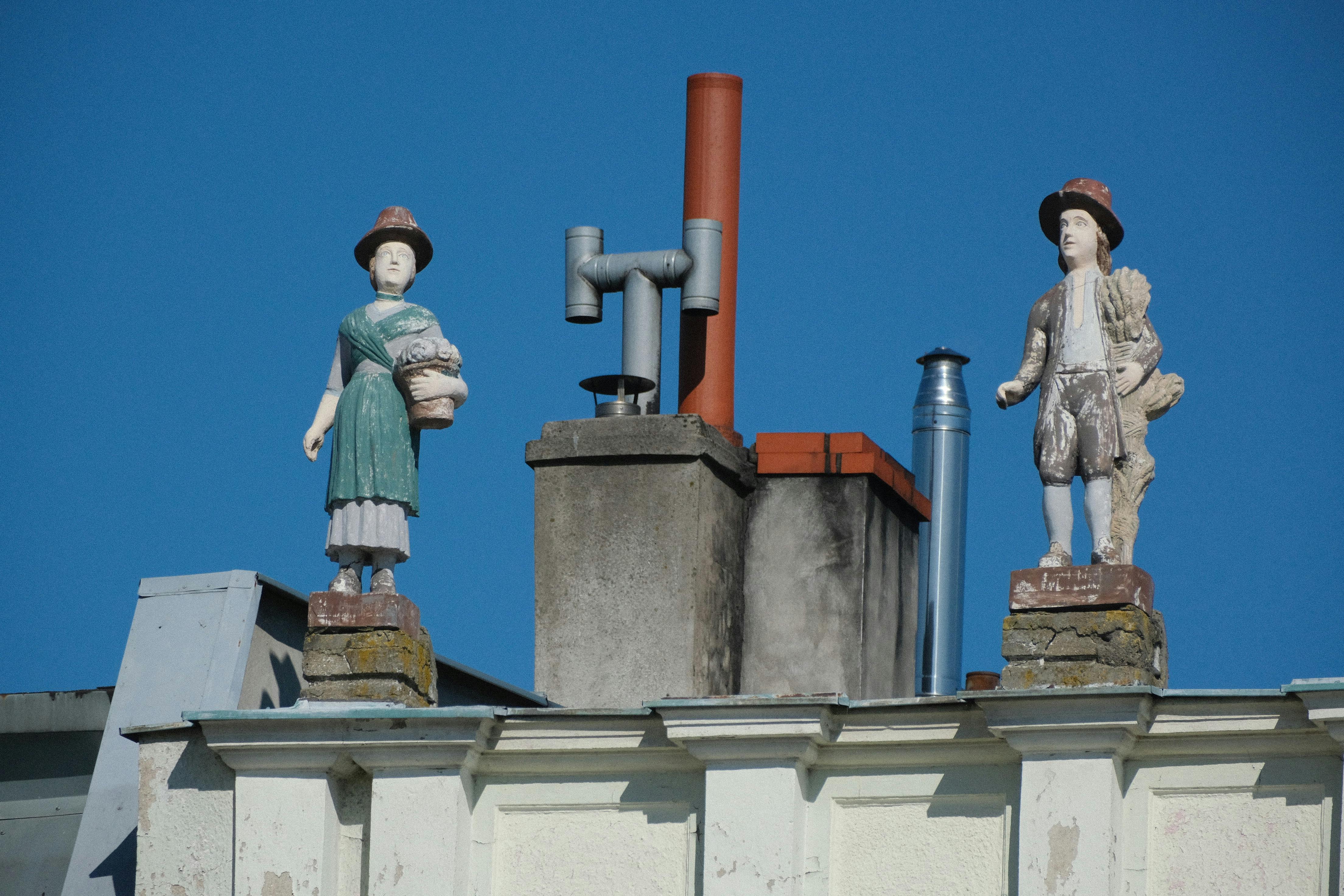 Stone Statues on Rooftop Against Clear Blue Sky · Free Stock Photo