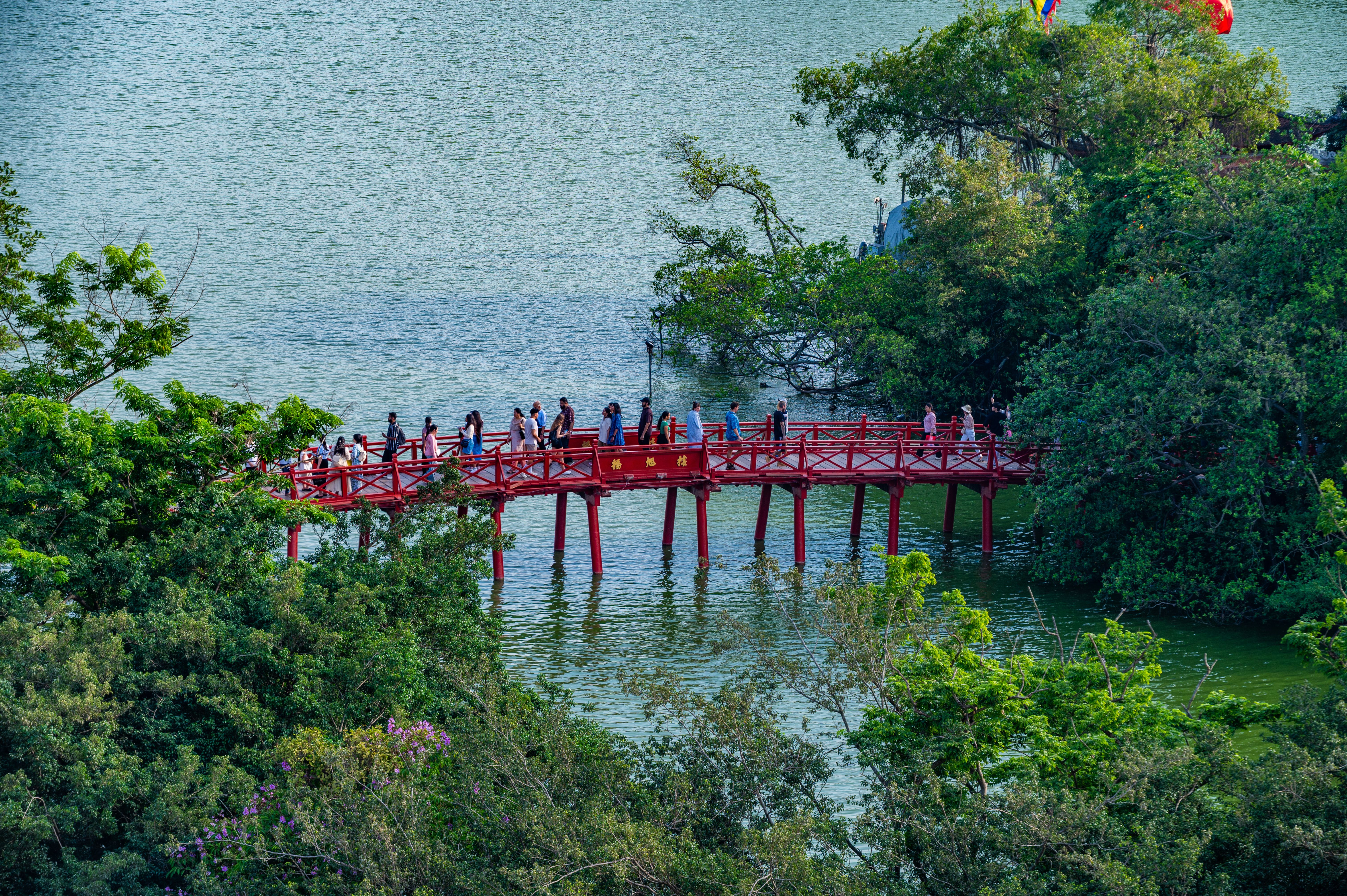 People Crossing The Red Bridge Over Tranquil Lake · Free Stock Photo