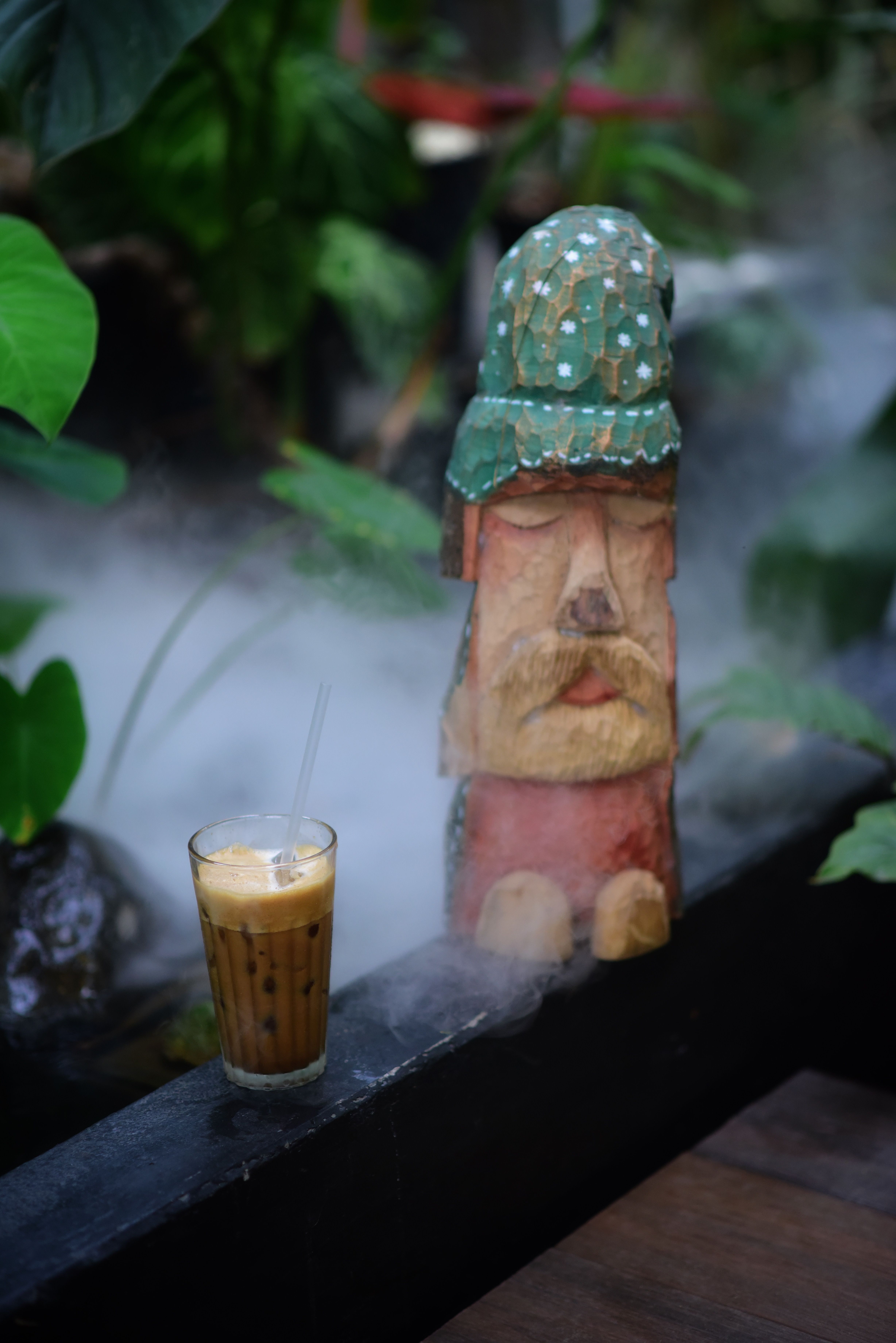 Wooden Statue with Iced Coffee in Misty Garden · Free Stock Photo