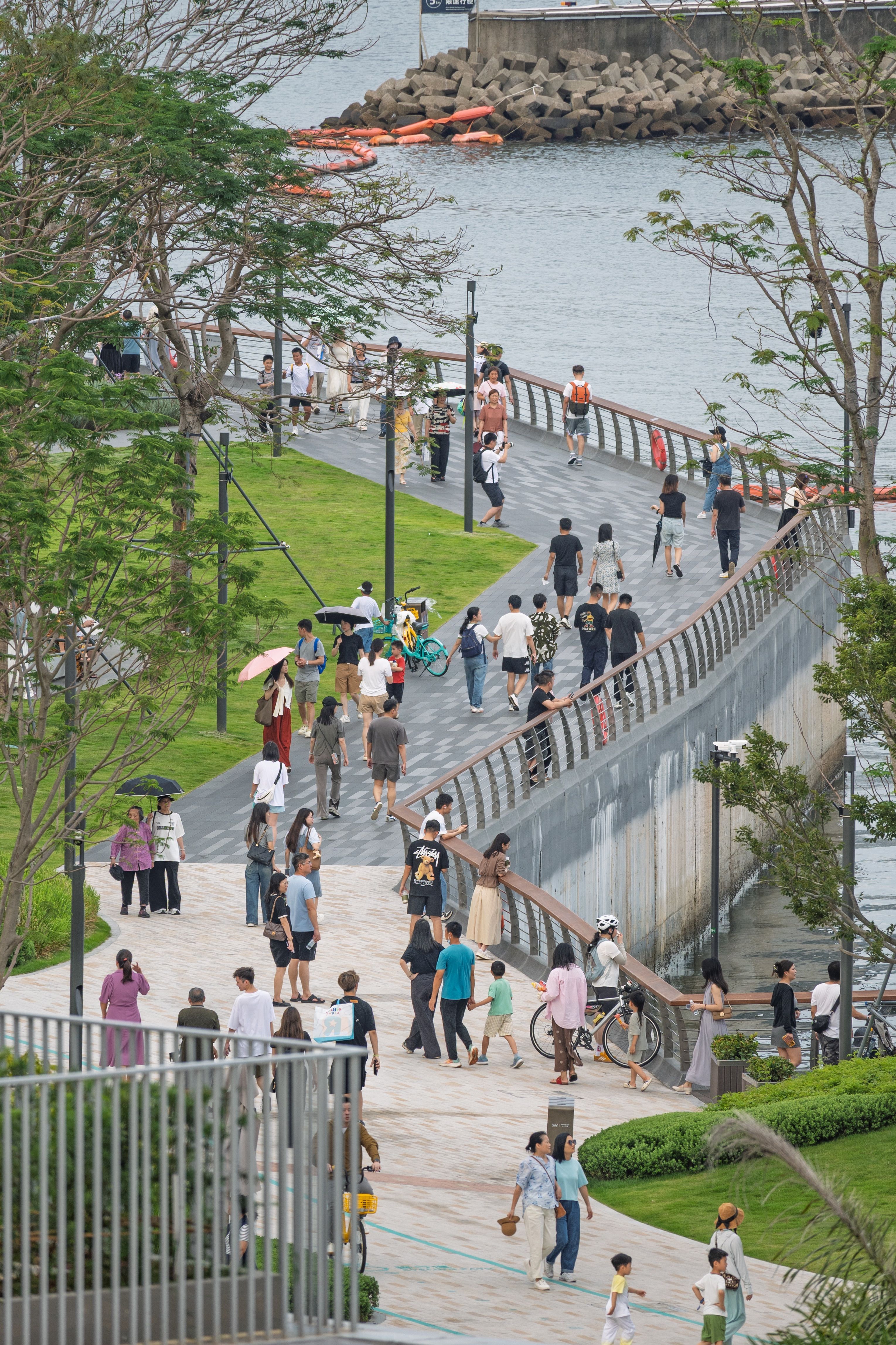 Crowded urban park walkway by the river · Free Stock Photo