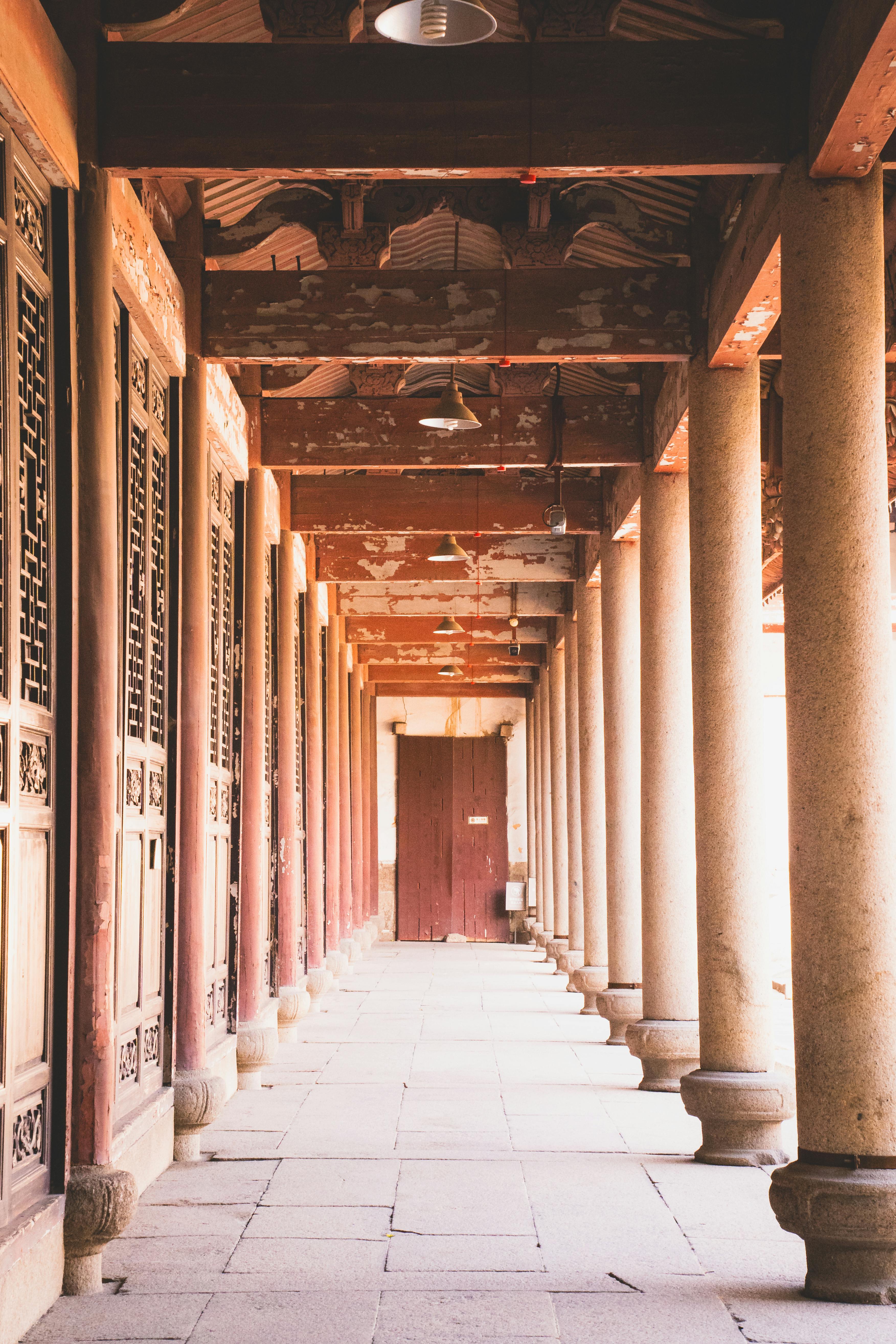 Ancient Corridor with Stone Columns and Wooden Doors · Free Stock Photo