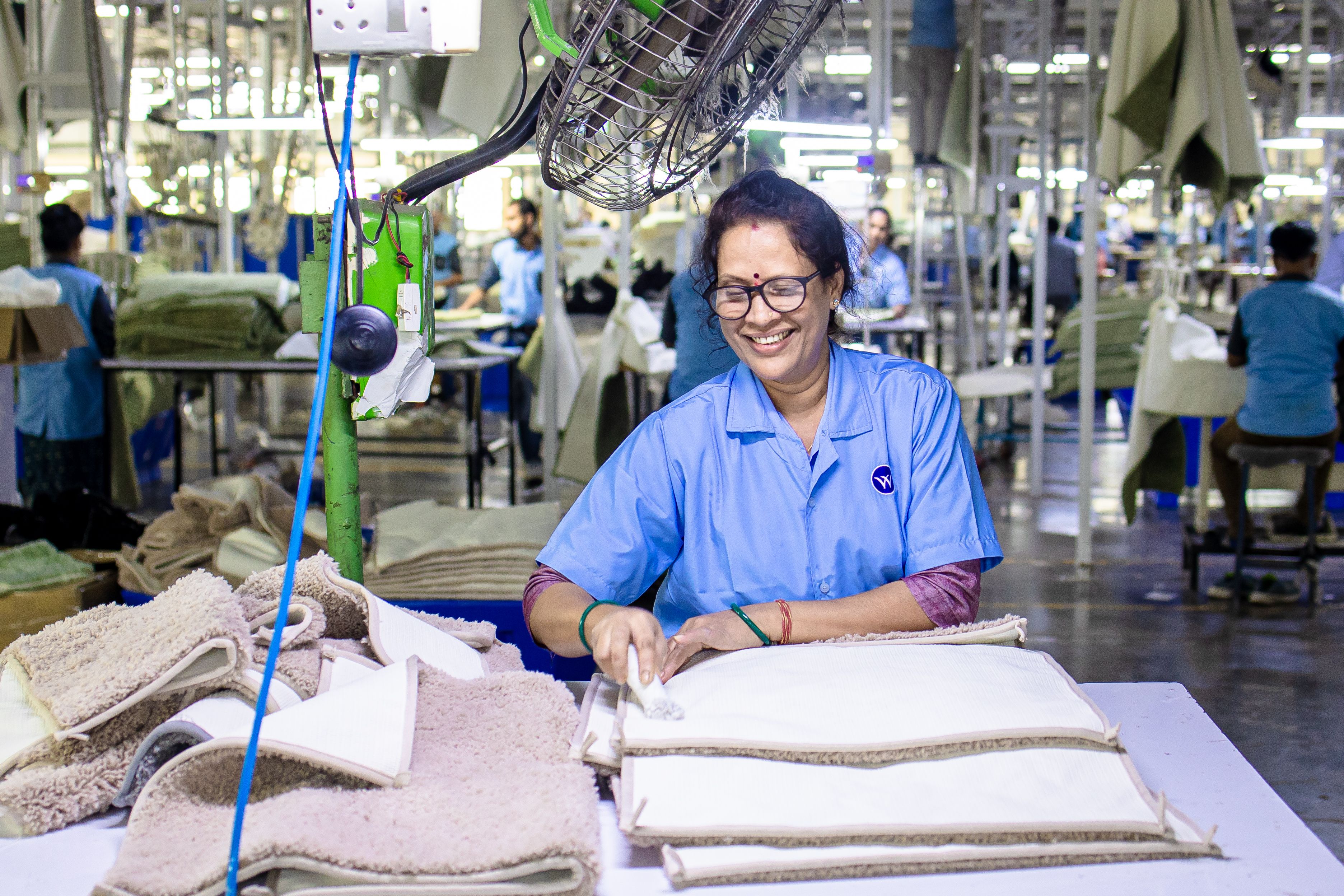 Smiling Textile Worker in a Bustling Factory · Free Stock Photo