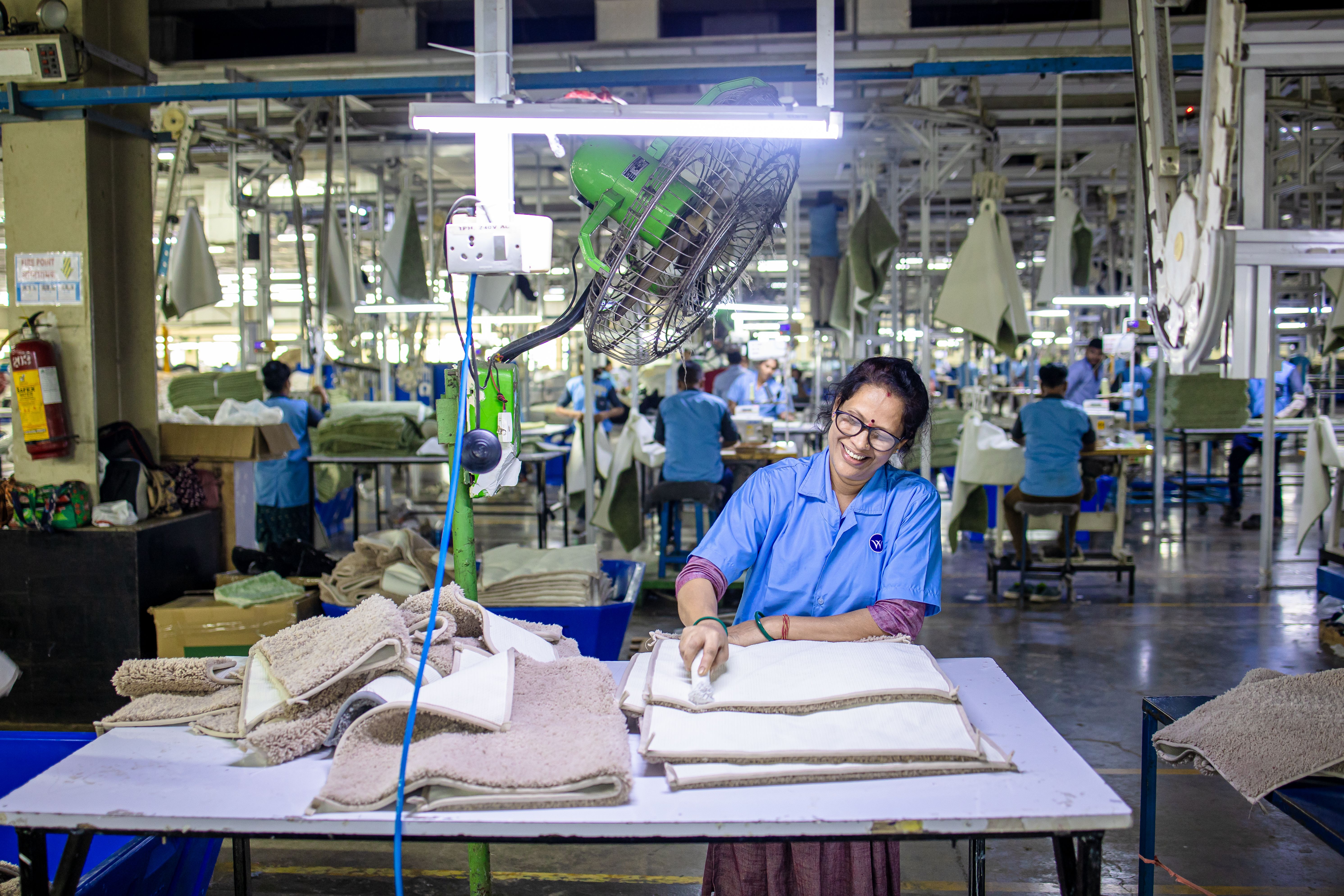 Smiling Textile Worker in a Bustling Factory · Free Stock Photo