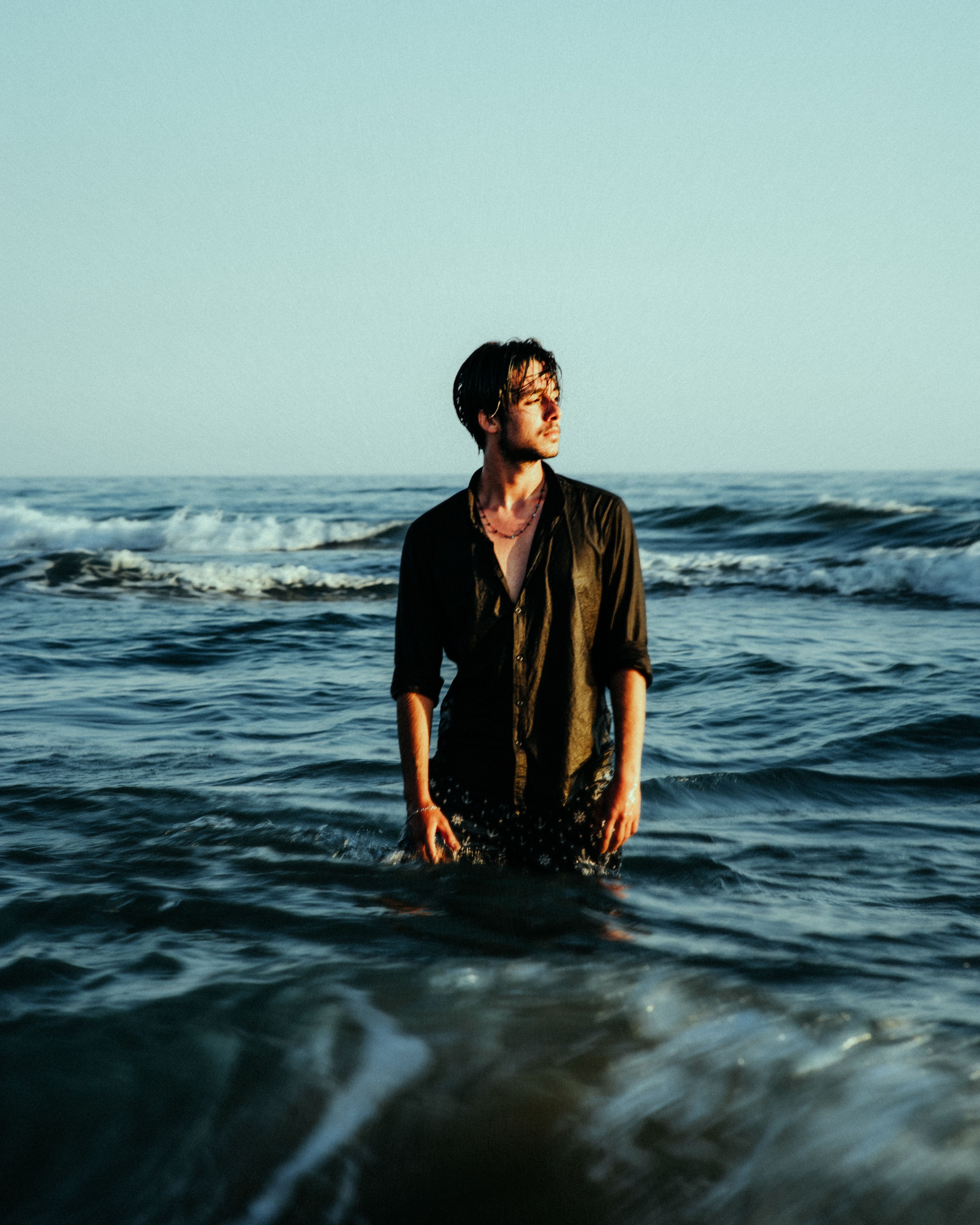 Young Man Standing in Ocean at Sunset · Free Stock Photo