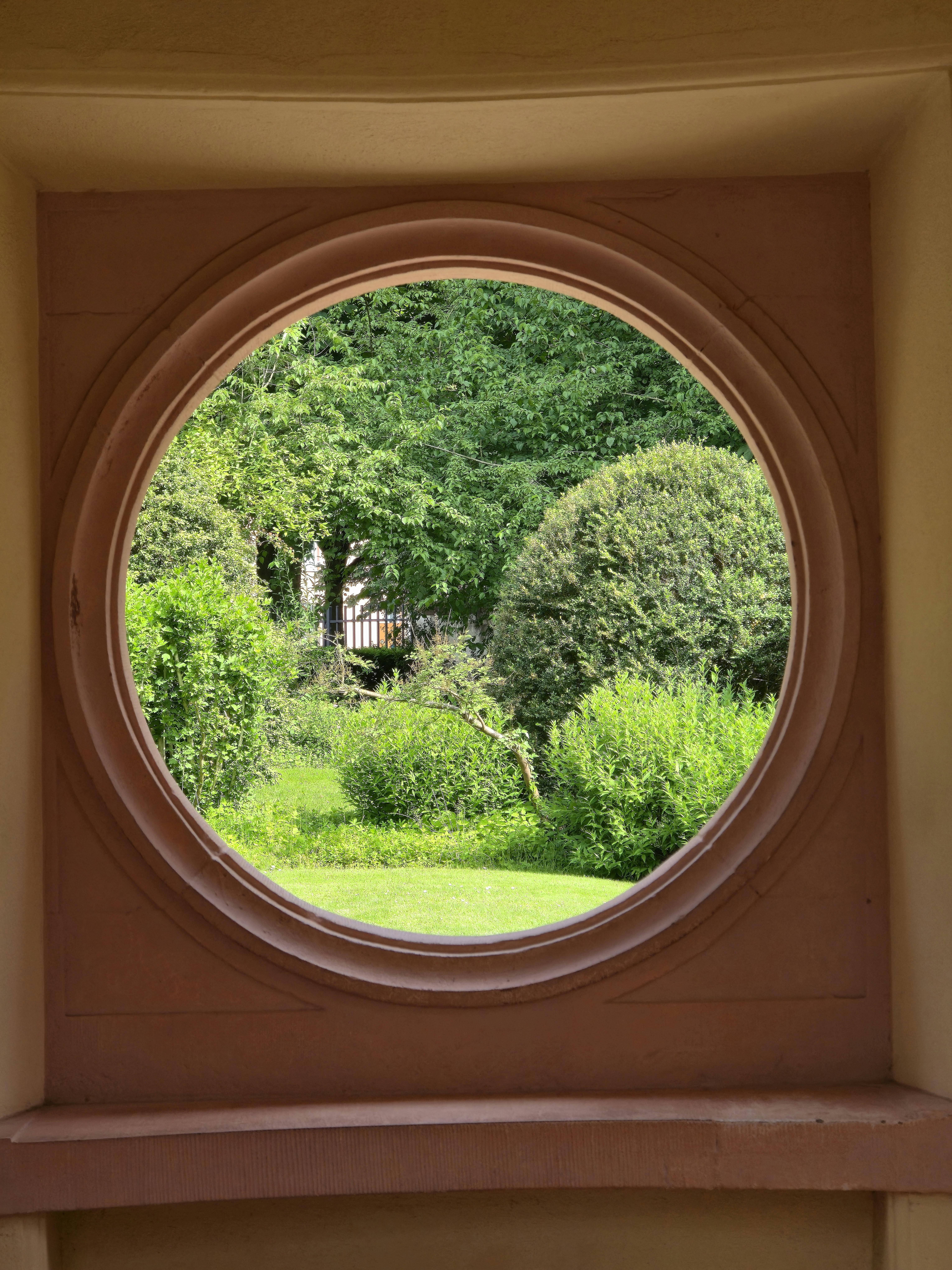 Round Window View of Lush Garden Landscape · Free Stock Photo