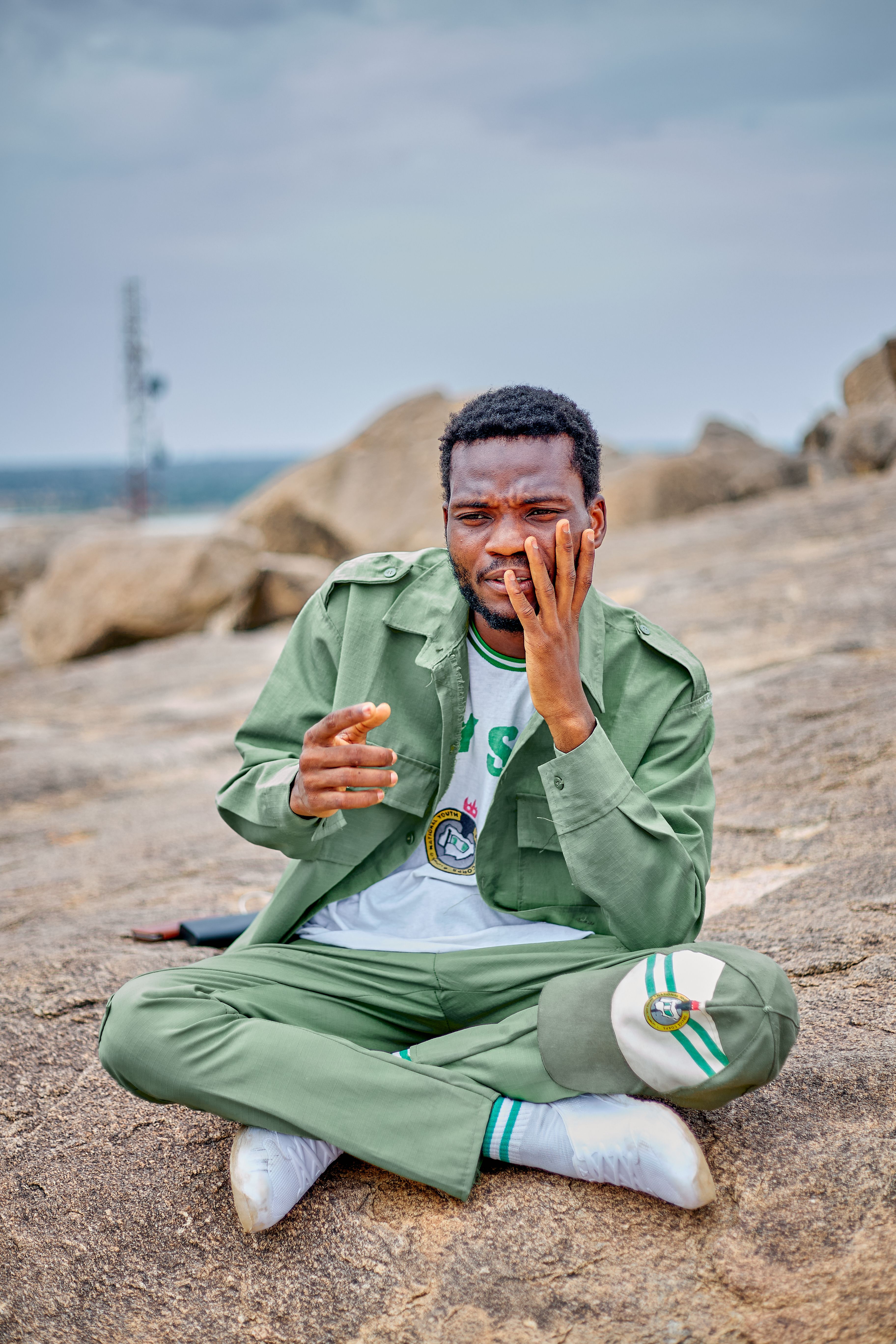 African man wearing green uniform sitting outdoors · Free Stock Photo