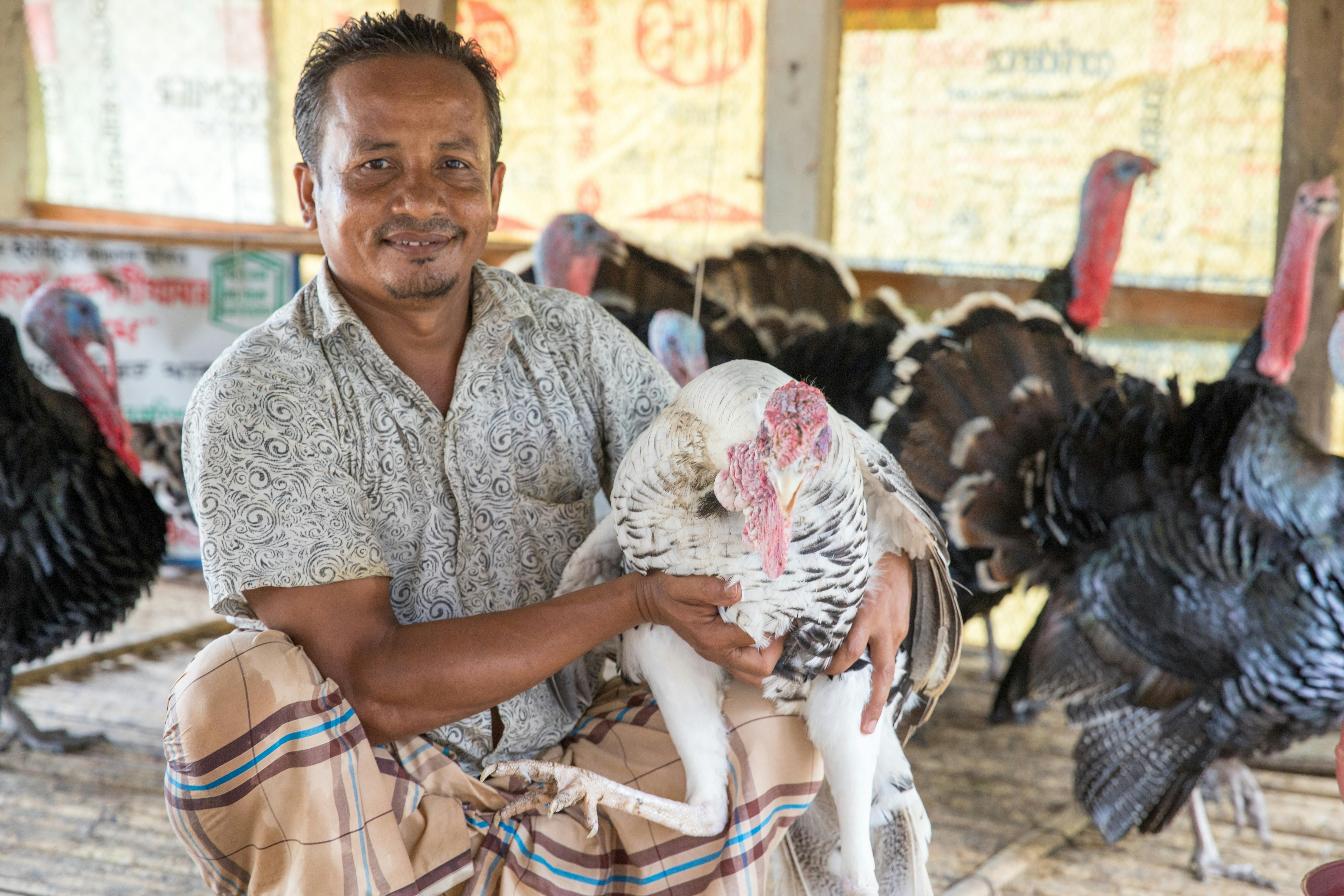 Smiling Farmer with Turkey at Poultry Farm in Bangladesh · Free Stock Photo