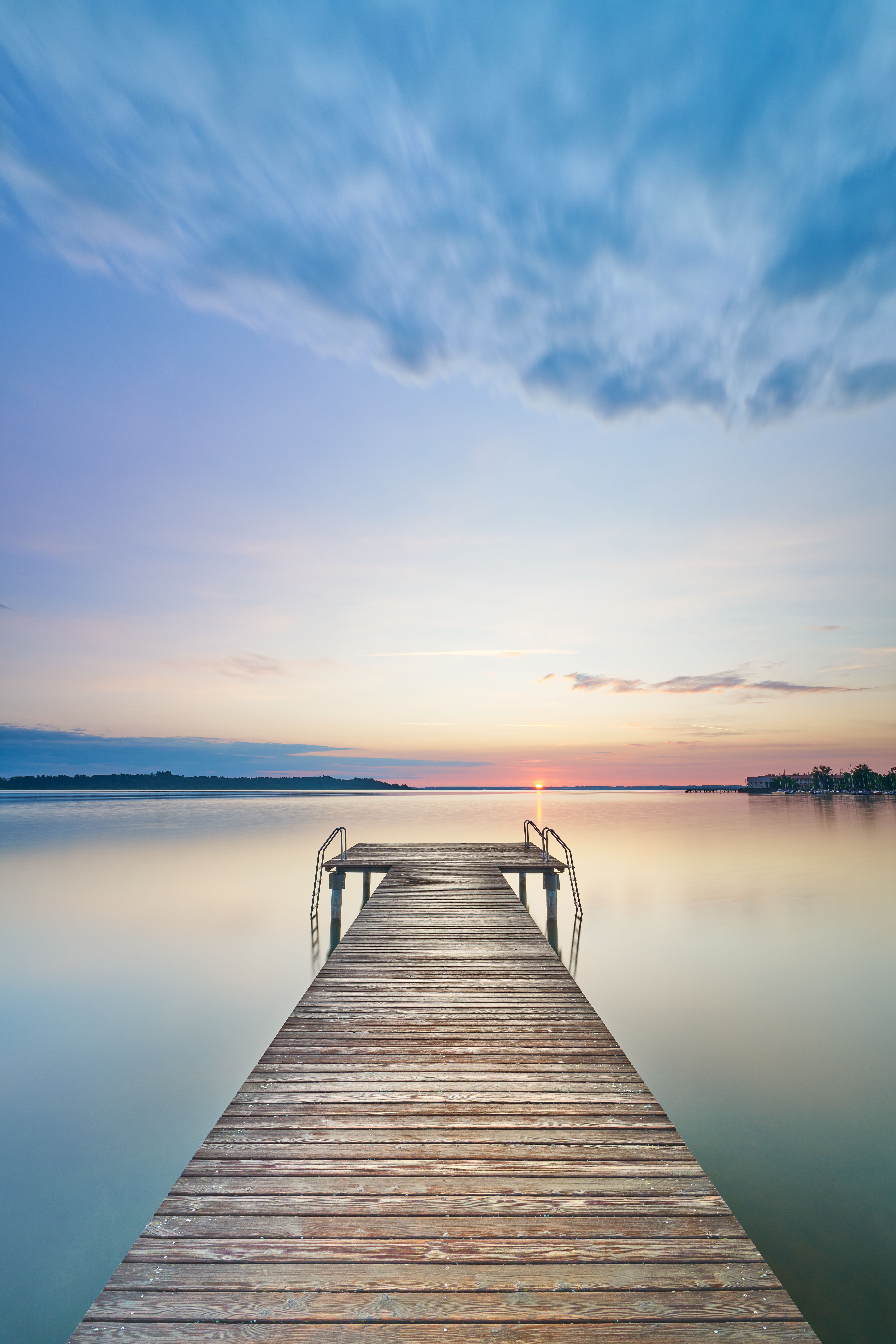 A wooden pier at sunset with water in the background · Free Stock Photo