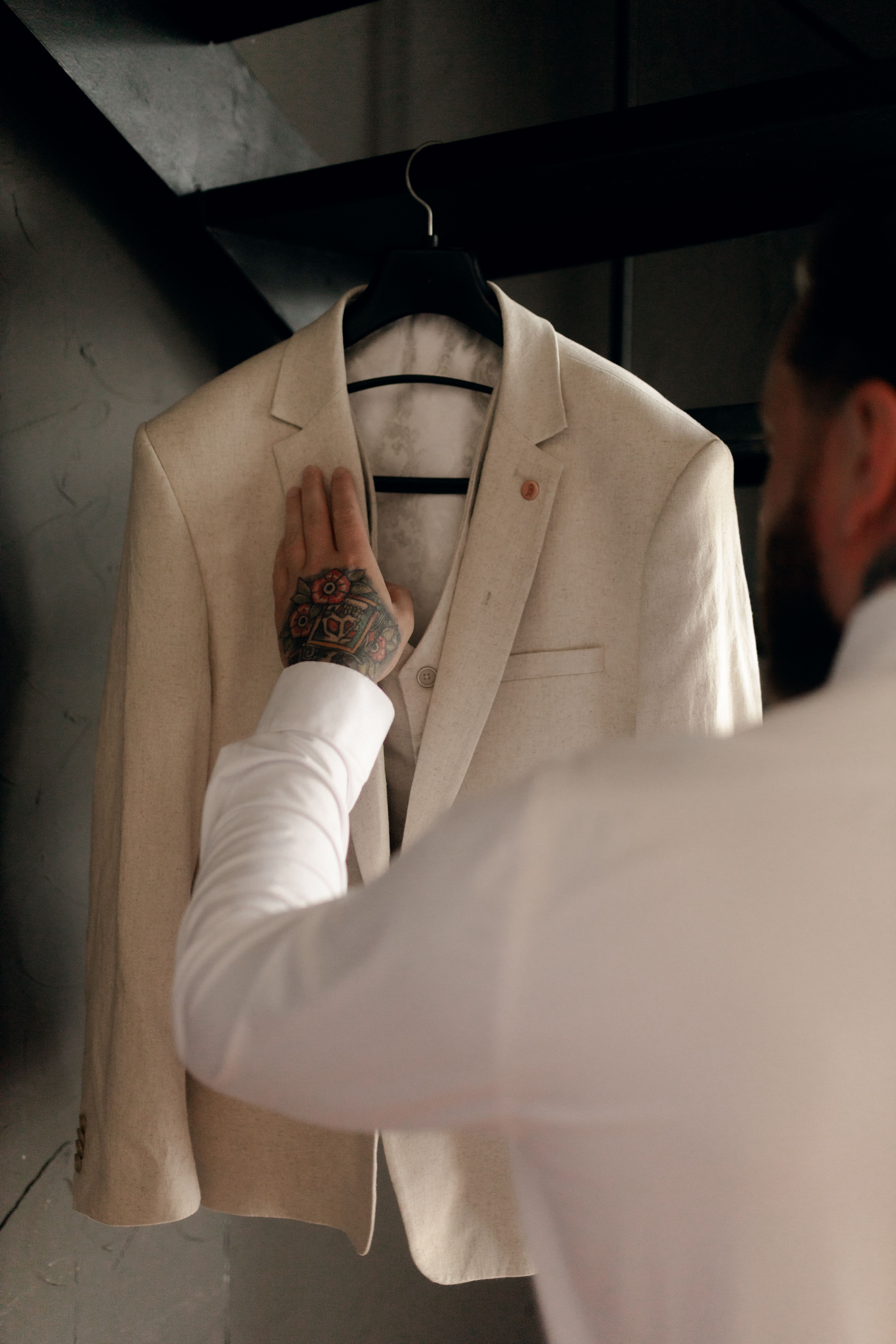 Man Adjusting Beige Suit Jacket on Hanger · Free Stock Photo