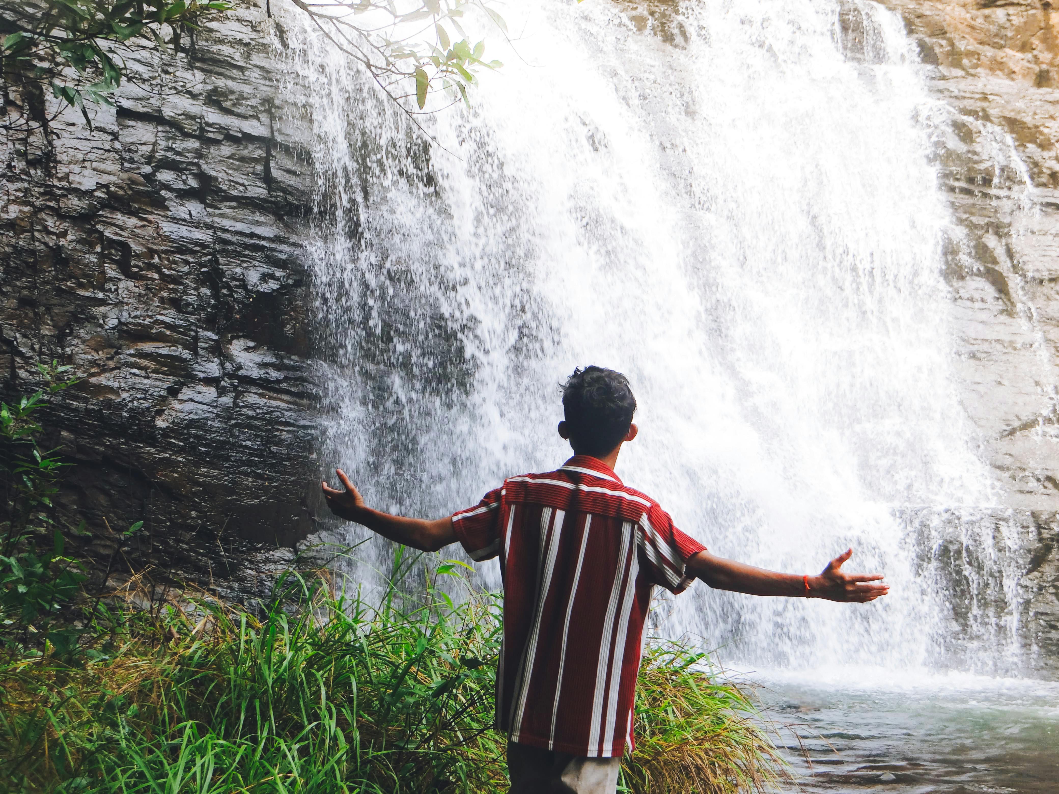 Man Embracing Nature Near a Waterfall · Free Stock Photo