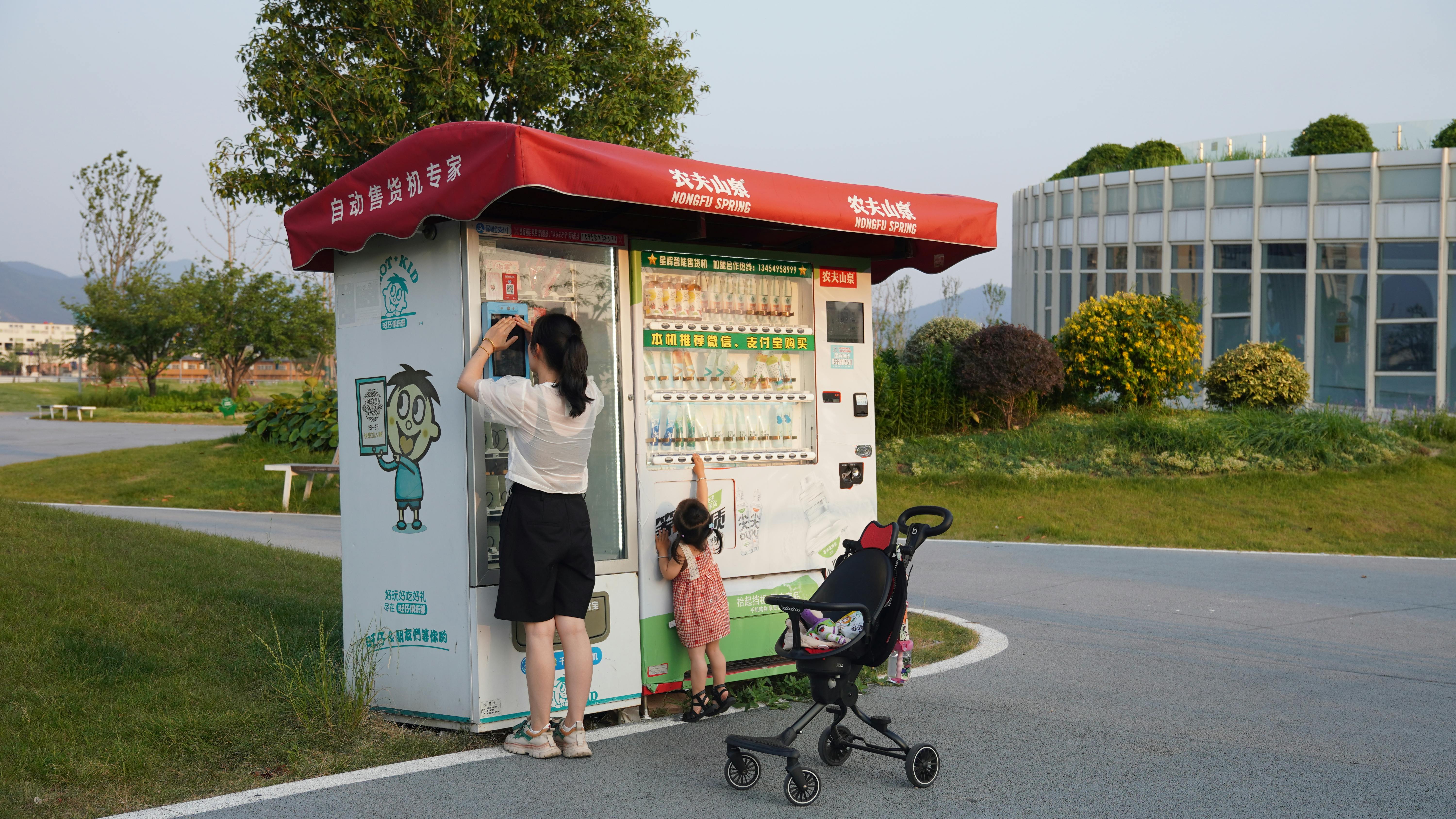 Mother and Child at a Vending Machine Outdoors · Free Stock Photo