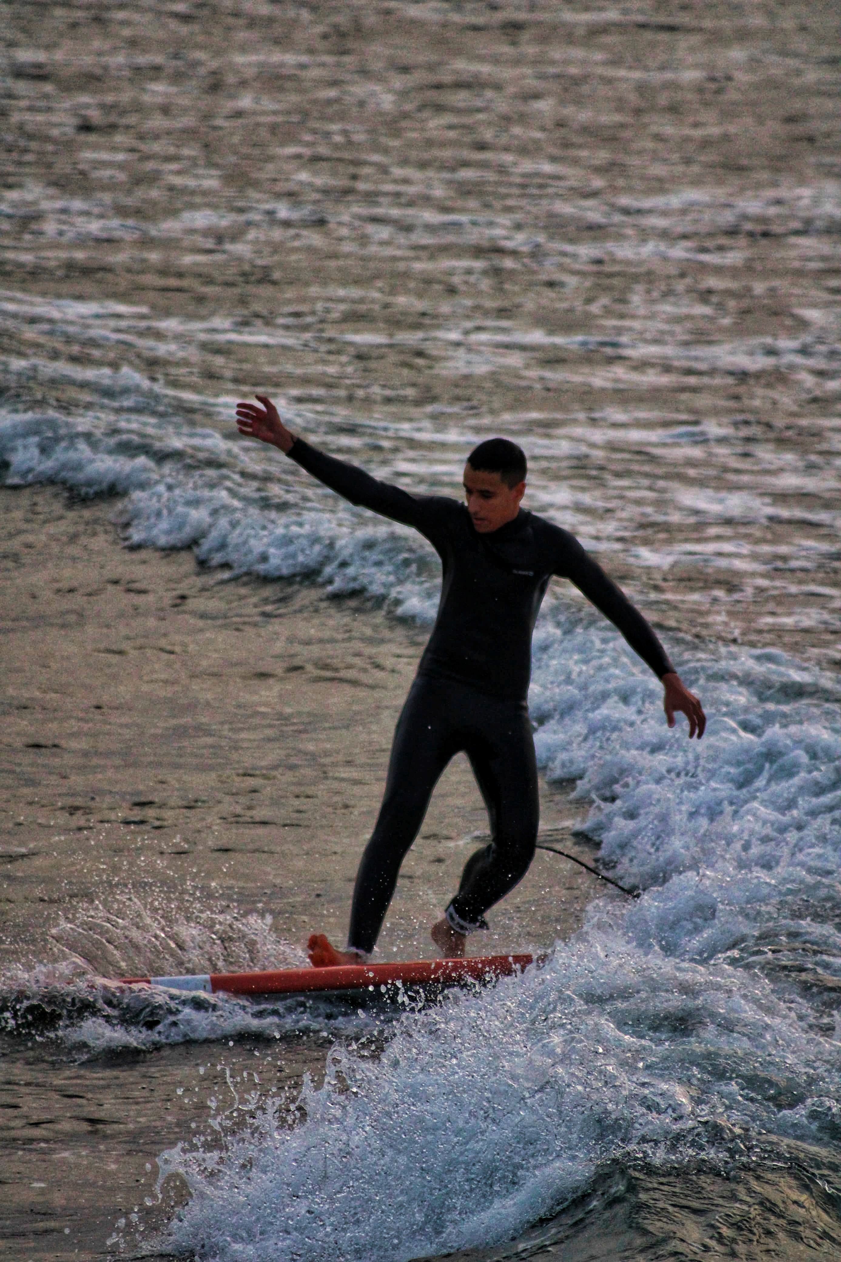 Surfer Balancing on Board in Ocean Waves at Sunset · Free Stock Photo