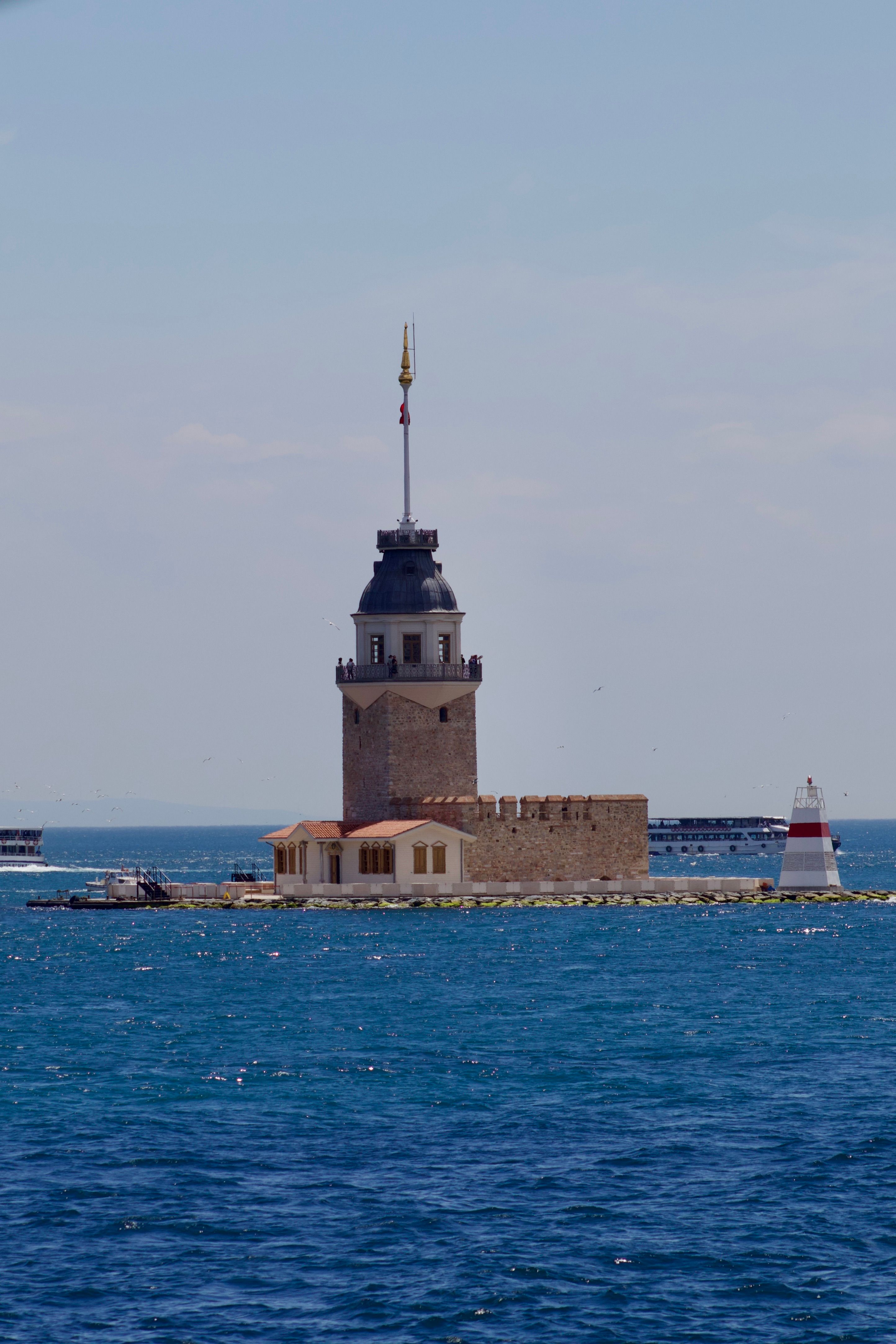 White Lighthouse Tower Beside Concrete Buildings · Free Stock Photo