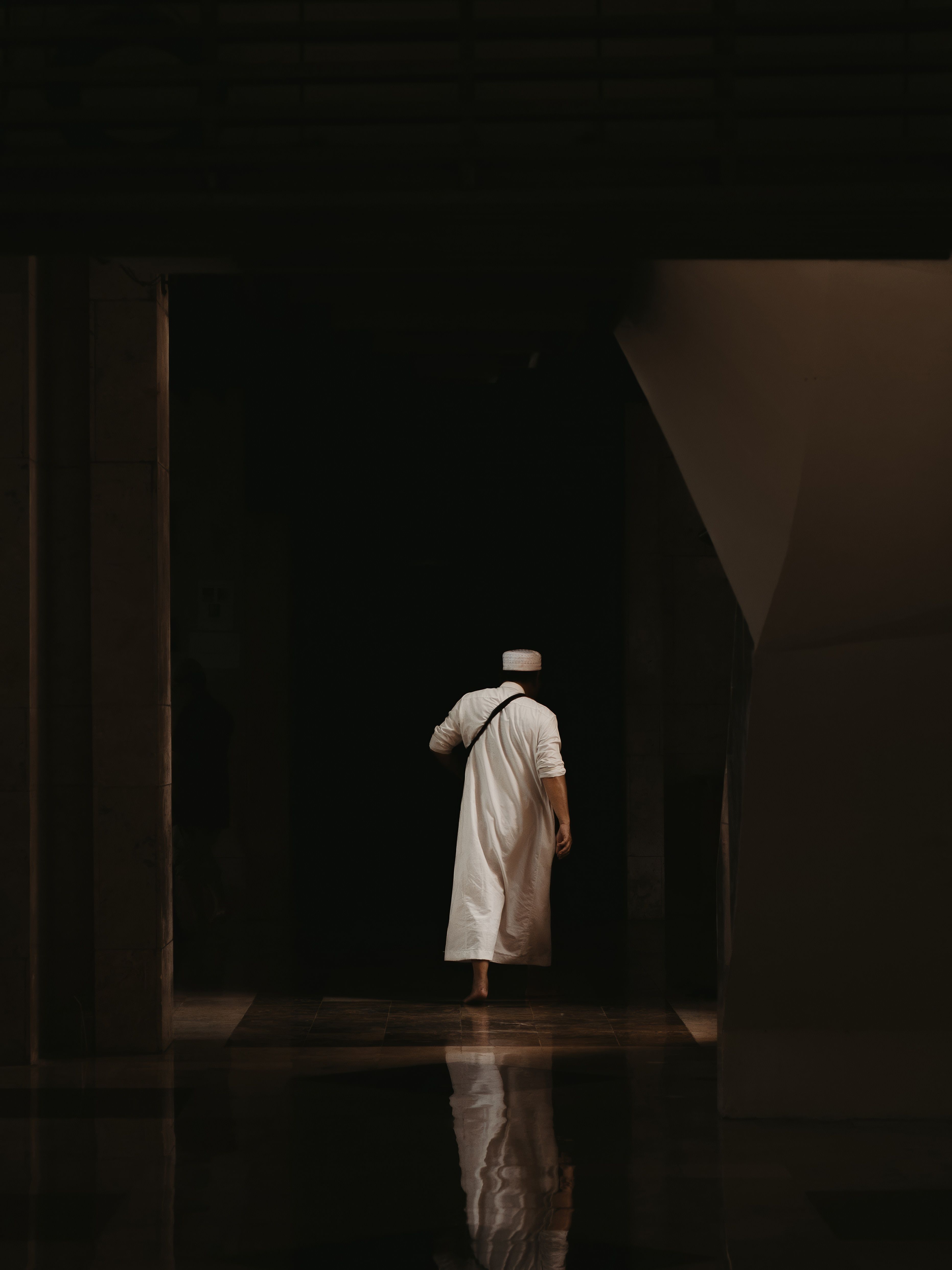 Un Homme En Robe Blanche Marchant Dans Un Couloir Sombre · Photo gratuite