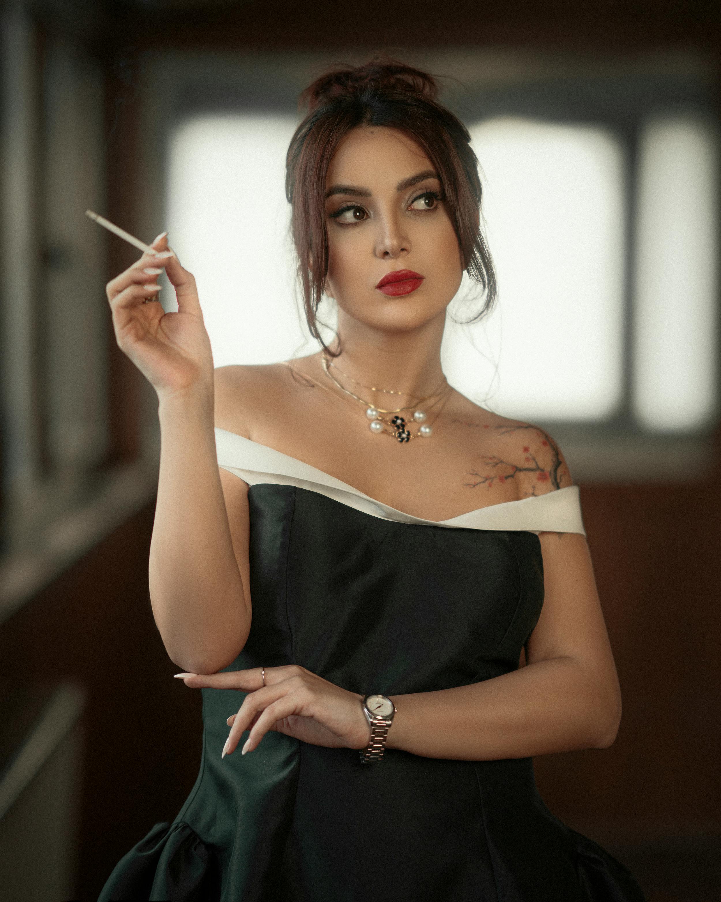 Elegant Woman Holding Cigarette in Chic Dress · Free Stock Photo