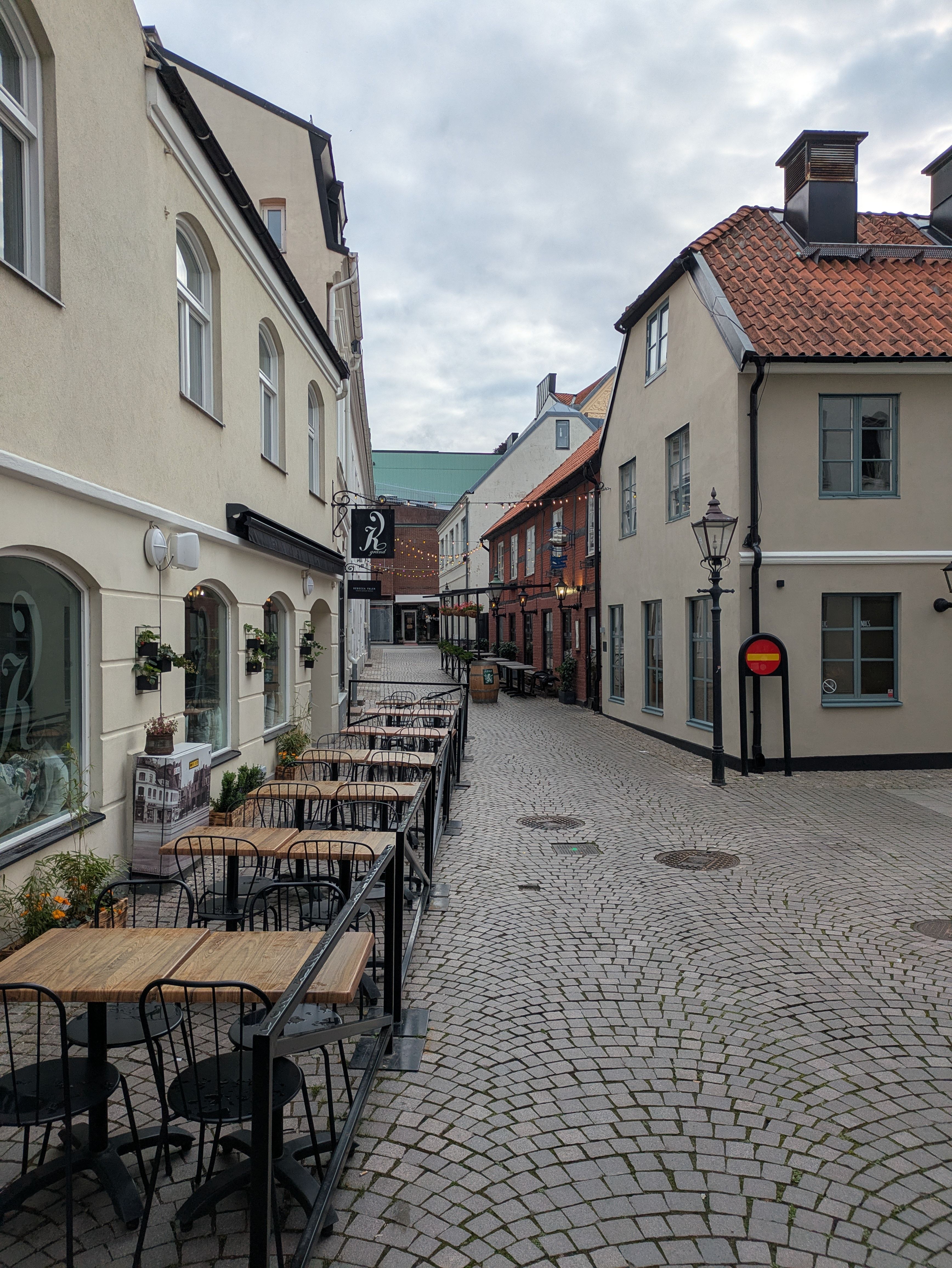 Charming Cobblestone Street with Outdoor Café Setting · Free Stock Photo